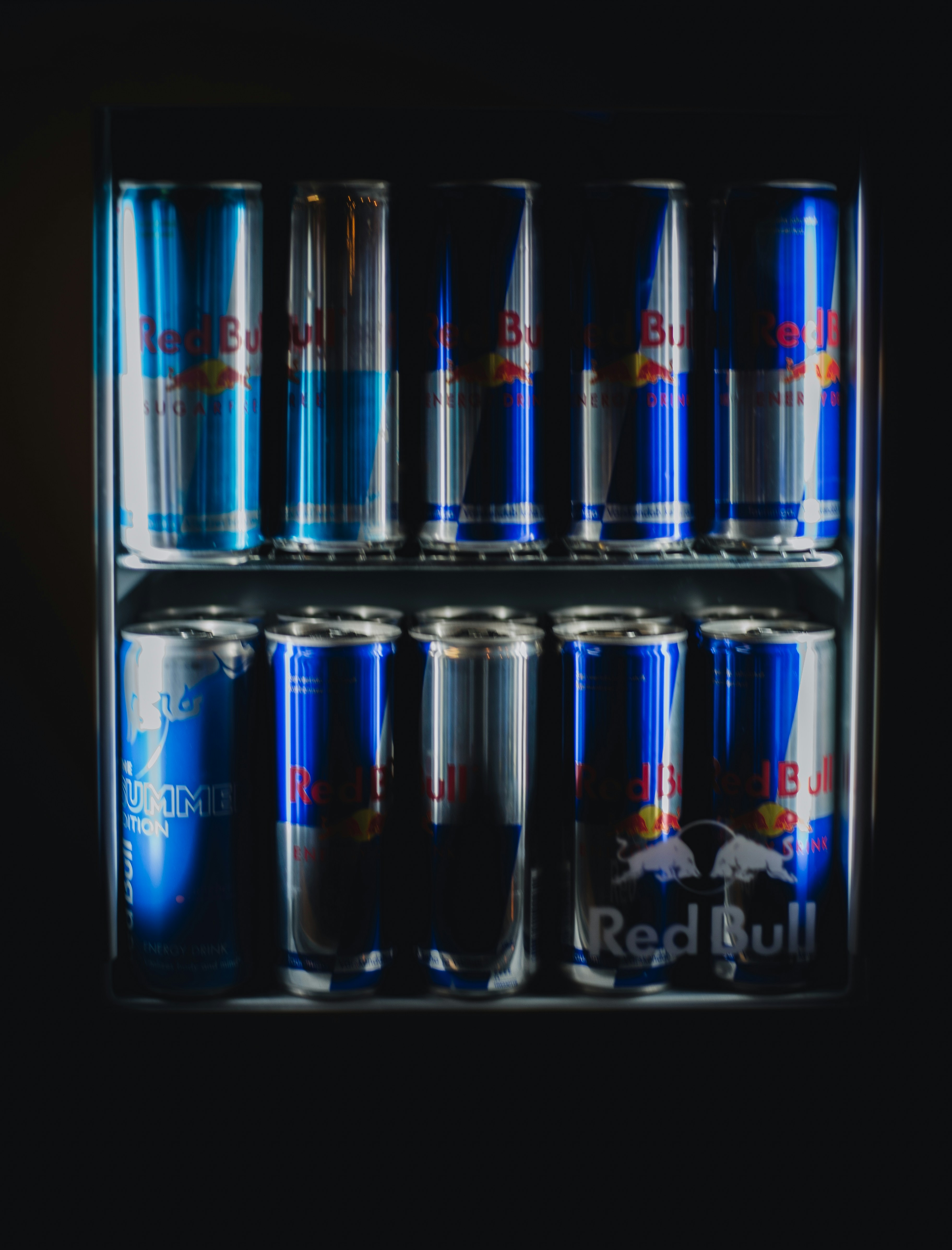 Midnight Glow: Neon-Blue Red Bull Cans in a Compact Fridge
