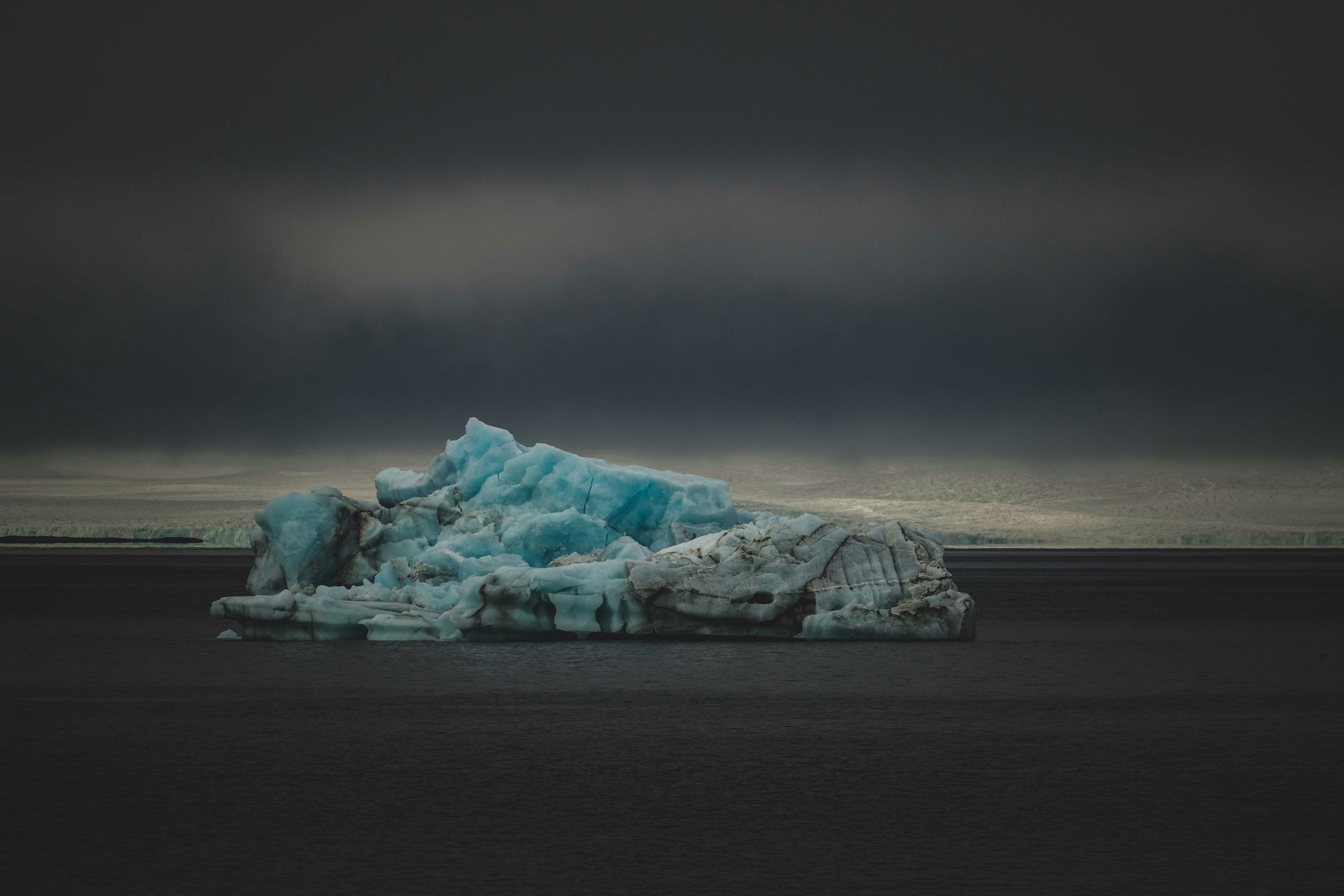 Blue Iceberg Against a Distant Storm: A Quiet Giant on Dark Seas