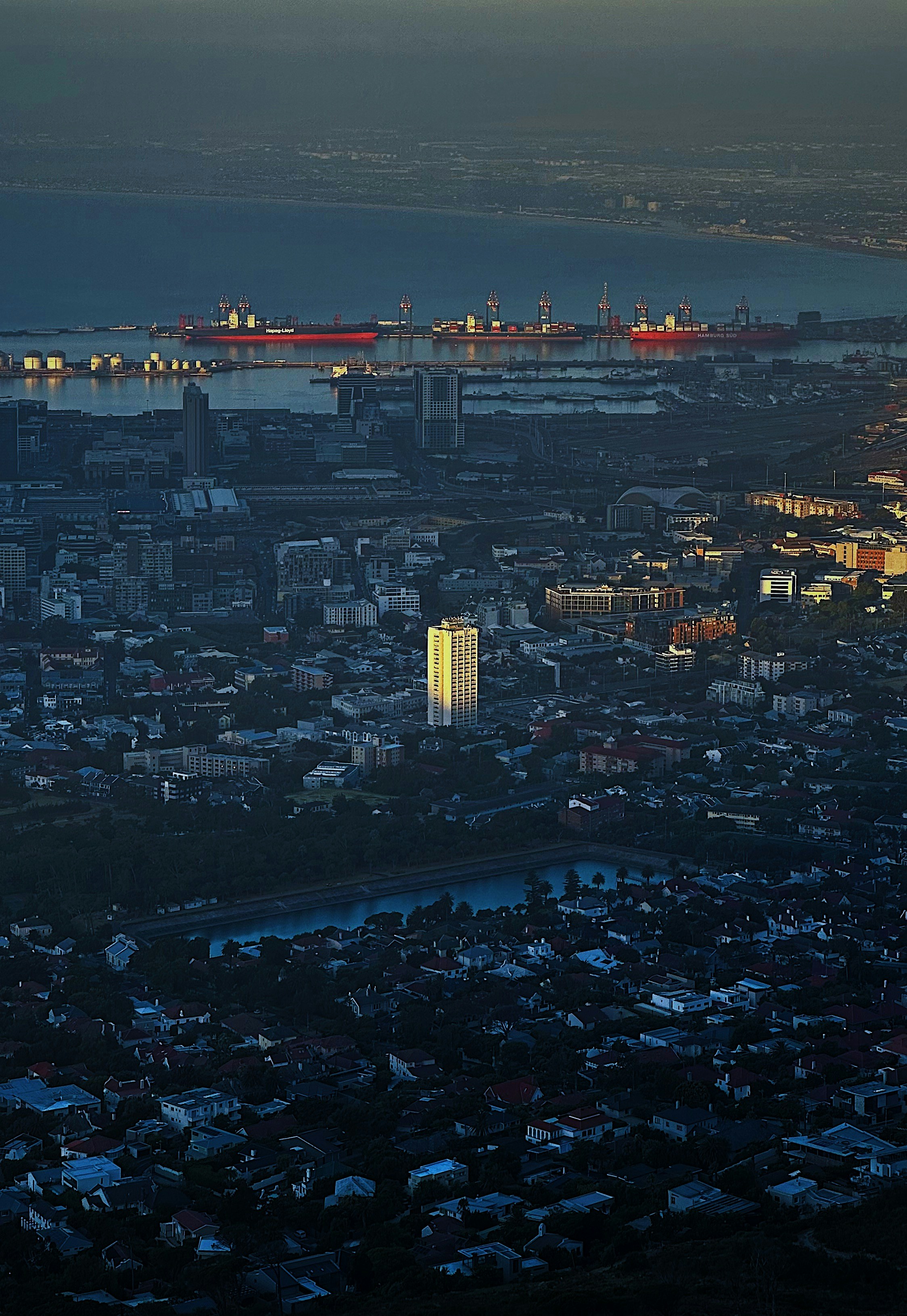 Sunlit Sentinel over the Harbor: A Cityscape with a Towering White High-Rise