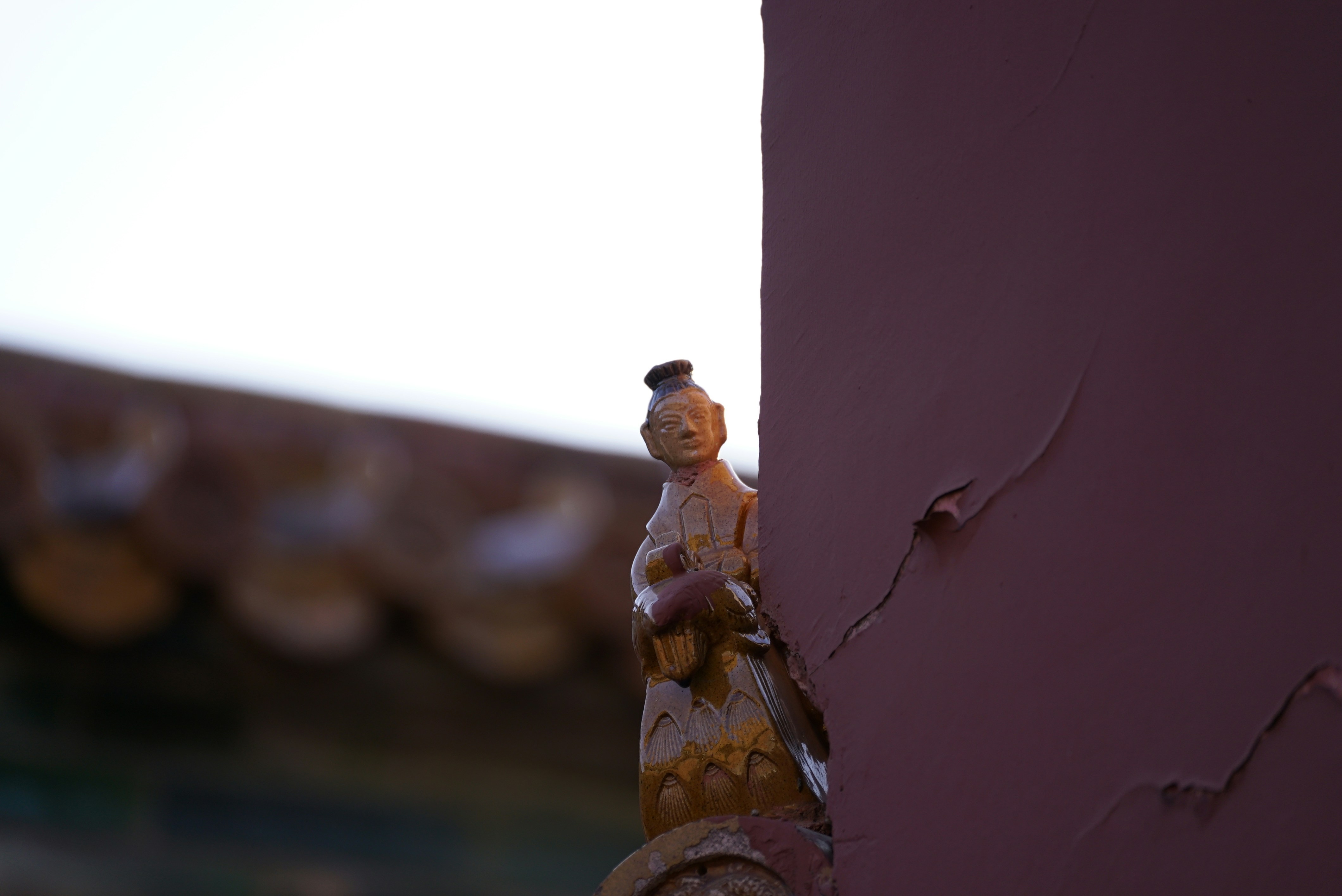 Tiny Sentinel Guarding a Cracked Pink Facade