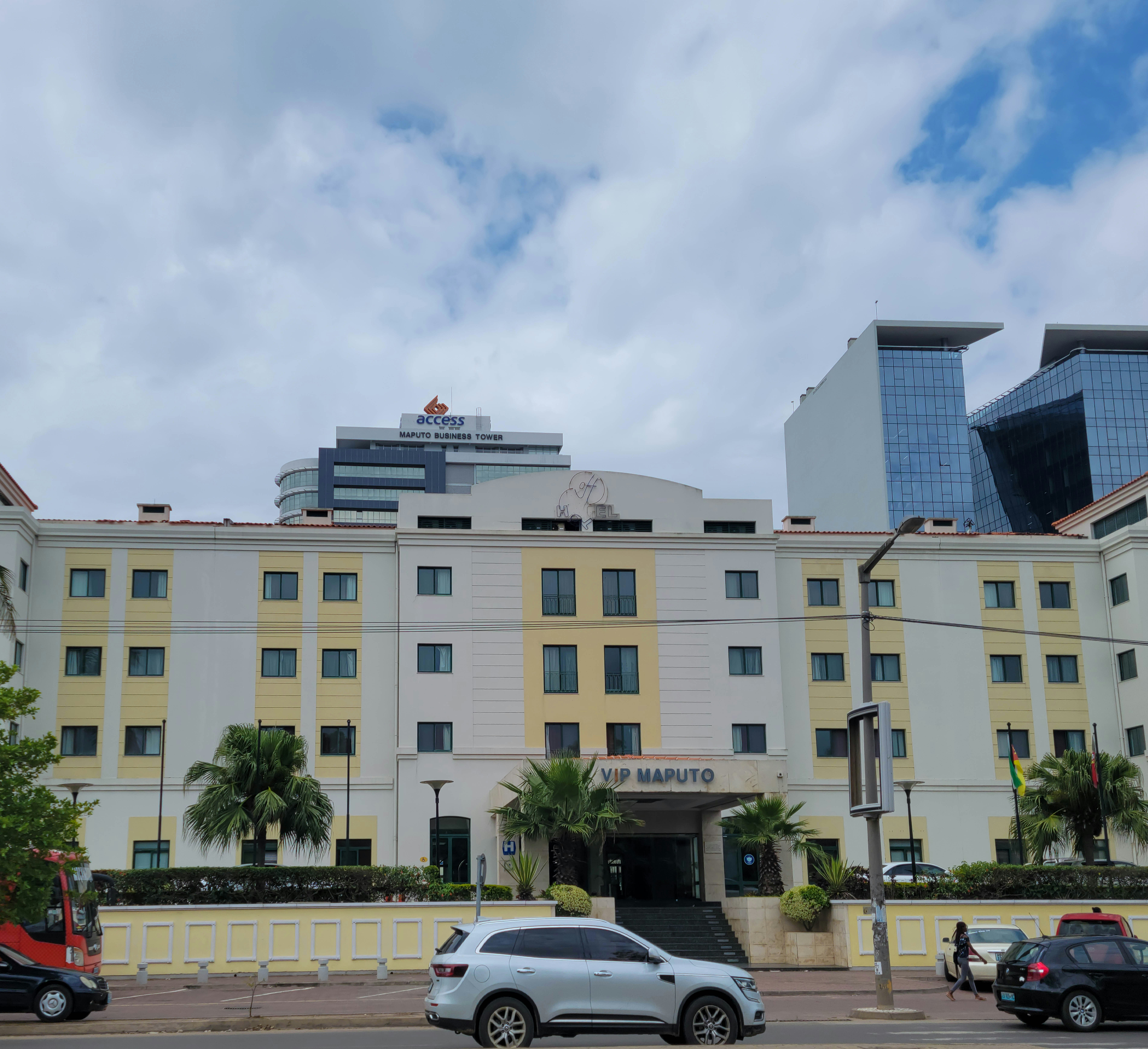 VIP Maputo Facade Framed by Palm Trees Under a Cloudy Skyline