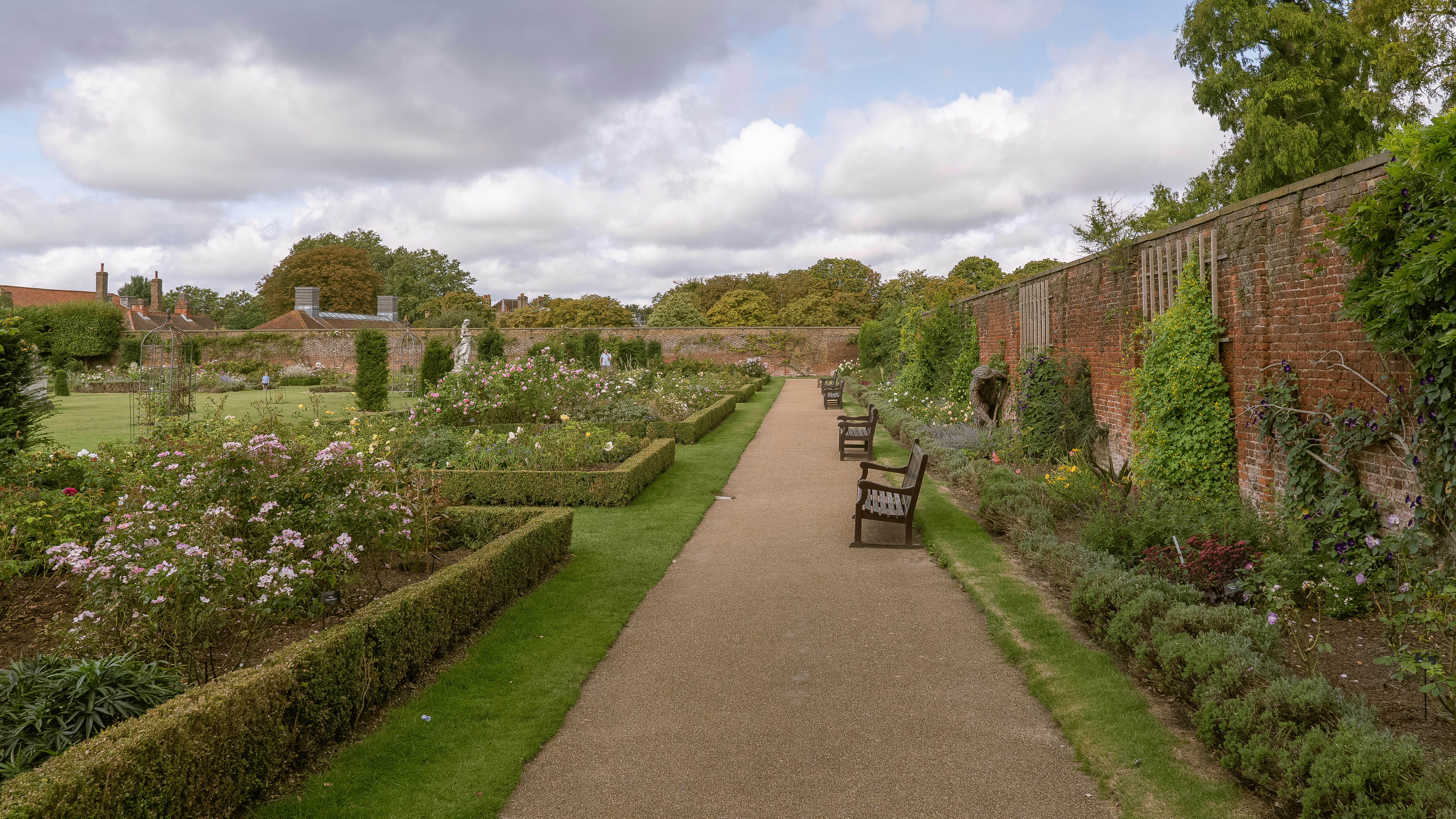 A garden with a path leading to a long row of hedges photo – Free ...