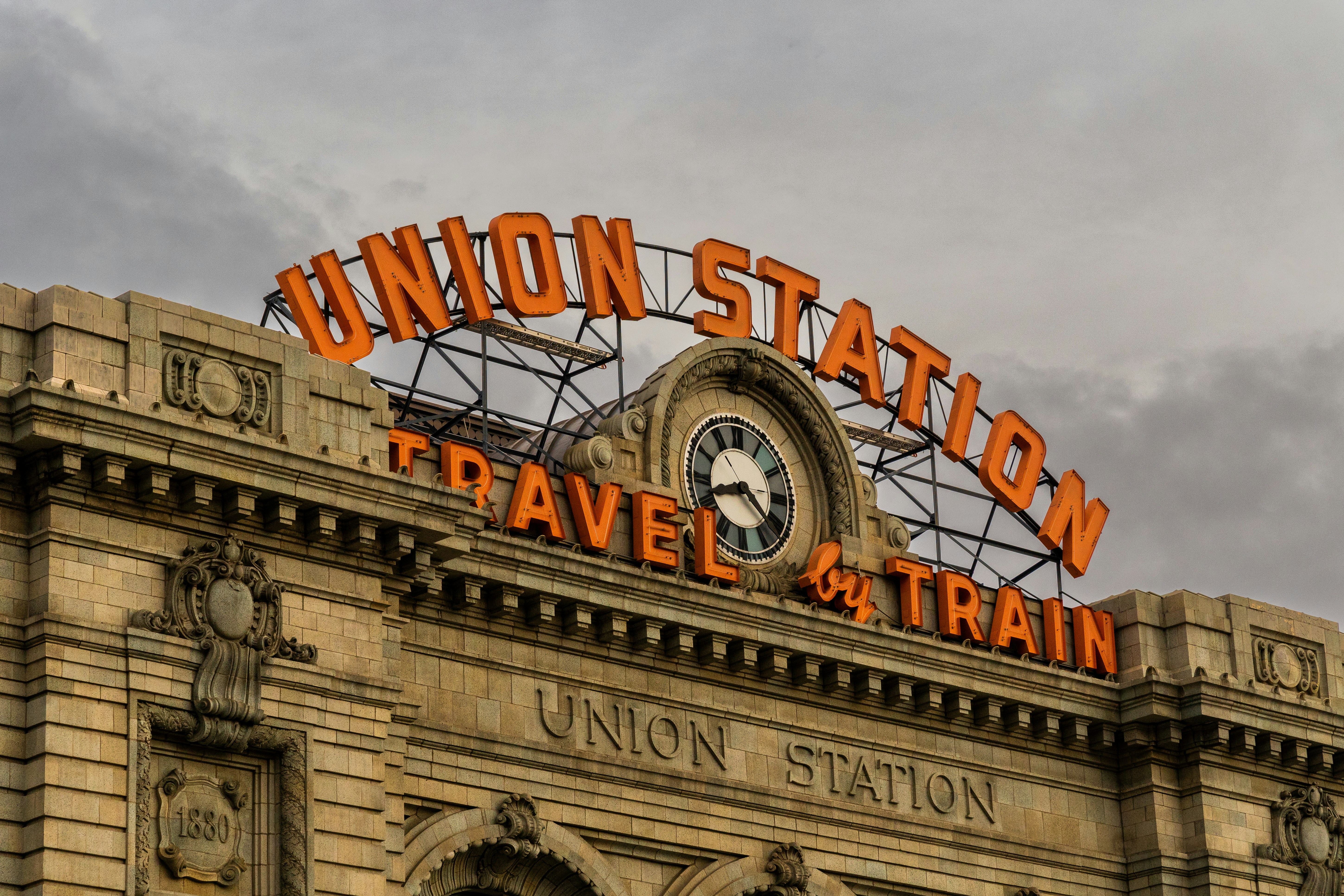 Historic Union Station facade featuring an iconic clock and vibrant signage promoting train travel.