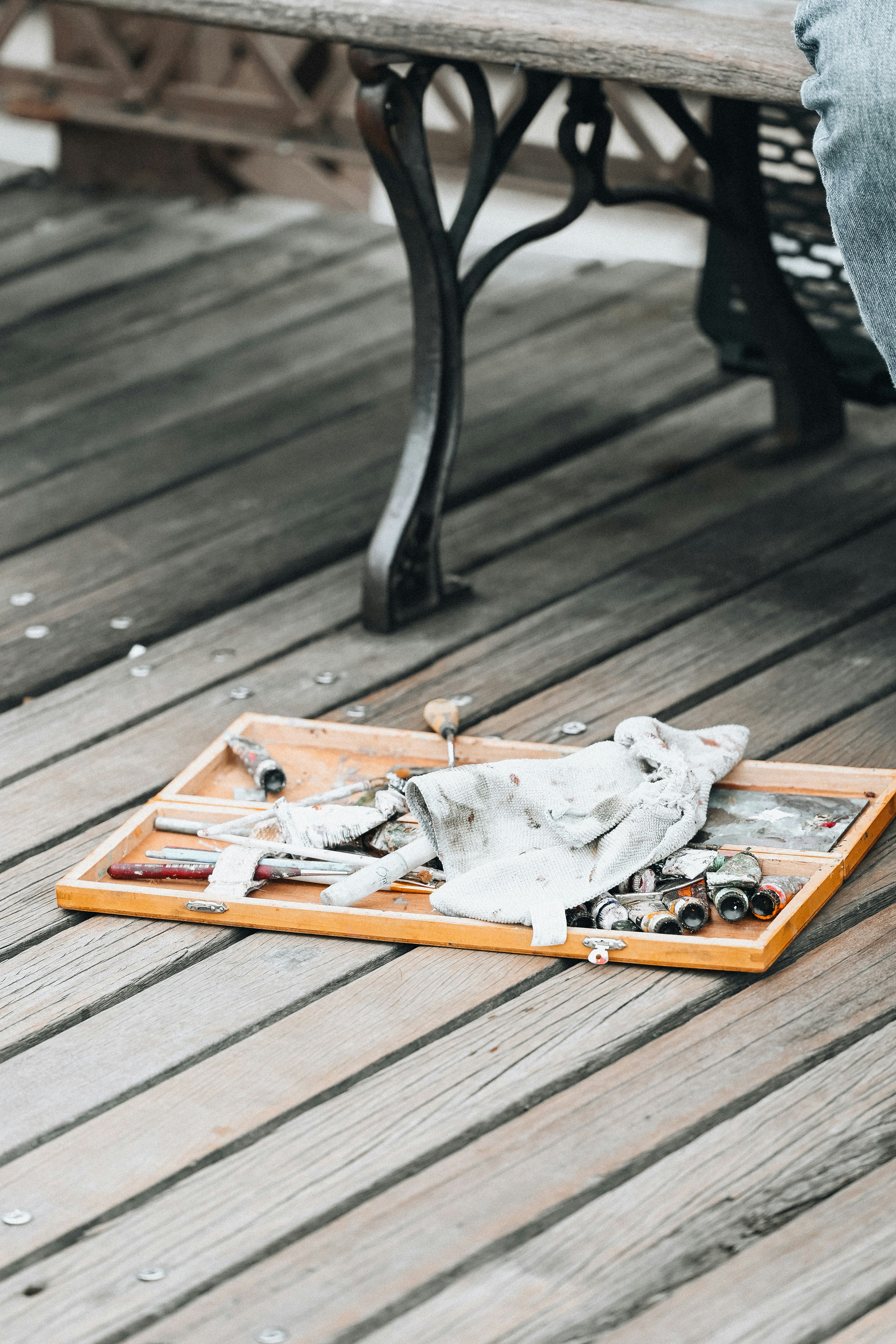 A Wooden Deck Tray of Tools and Rags Beneath a Park Bench