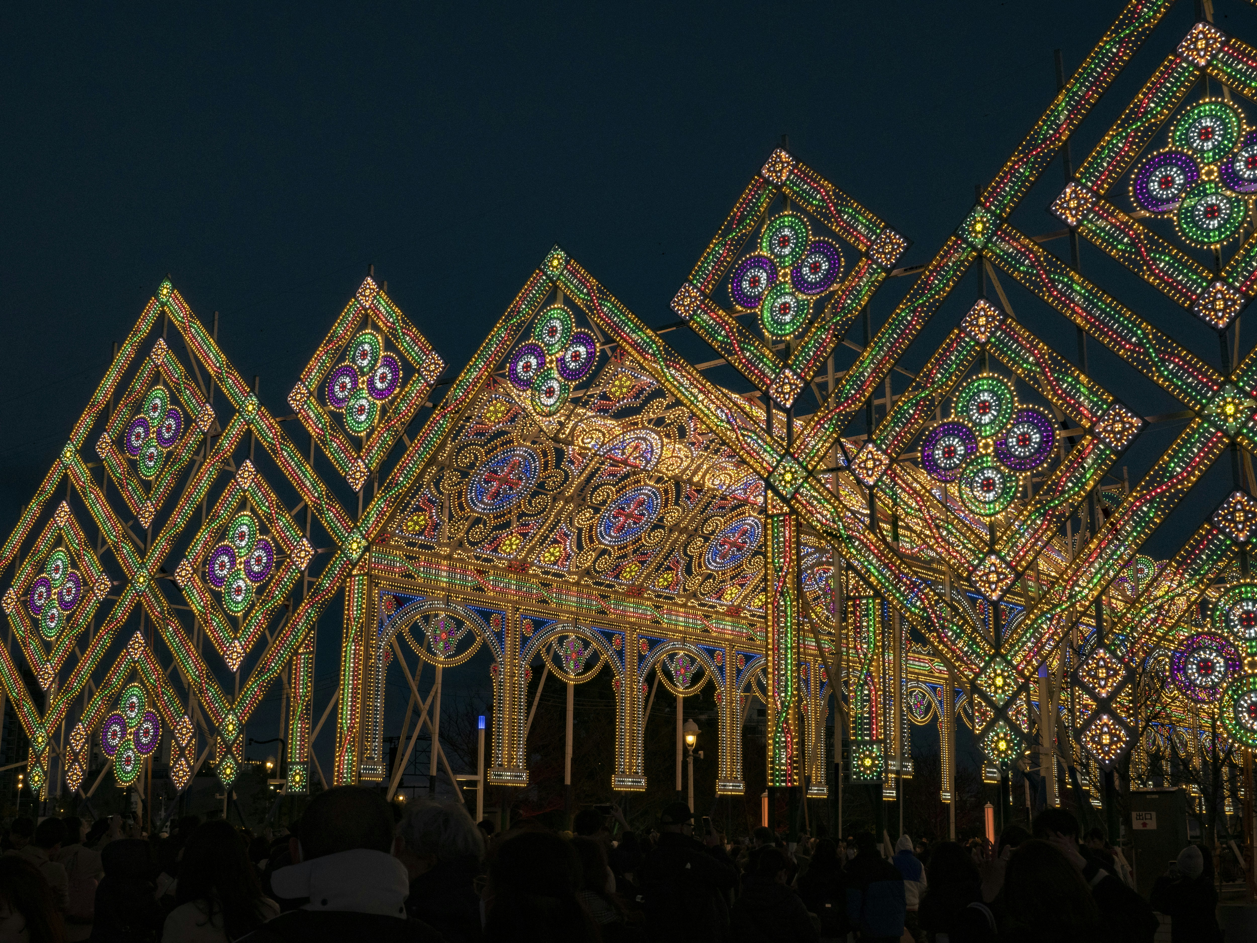 A group of people standing around a building covered in lights photo ...