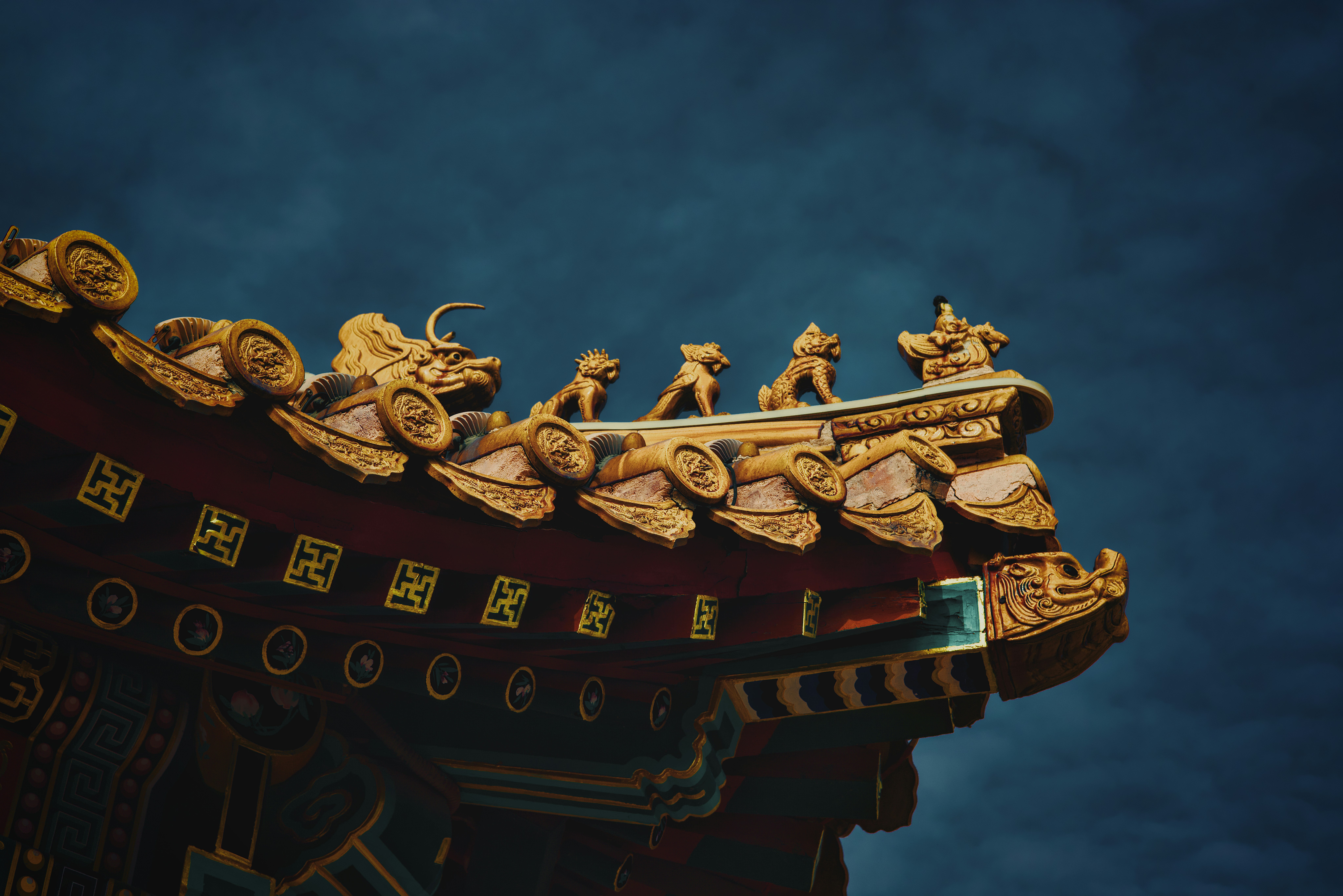 Ornate architectural roof detail with mythological figures set against a deep blue sky.