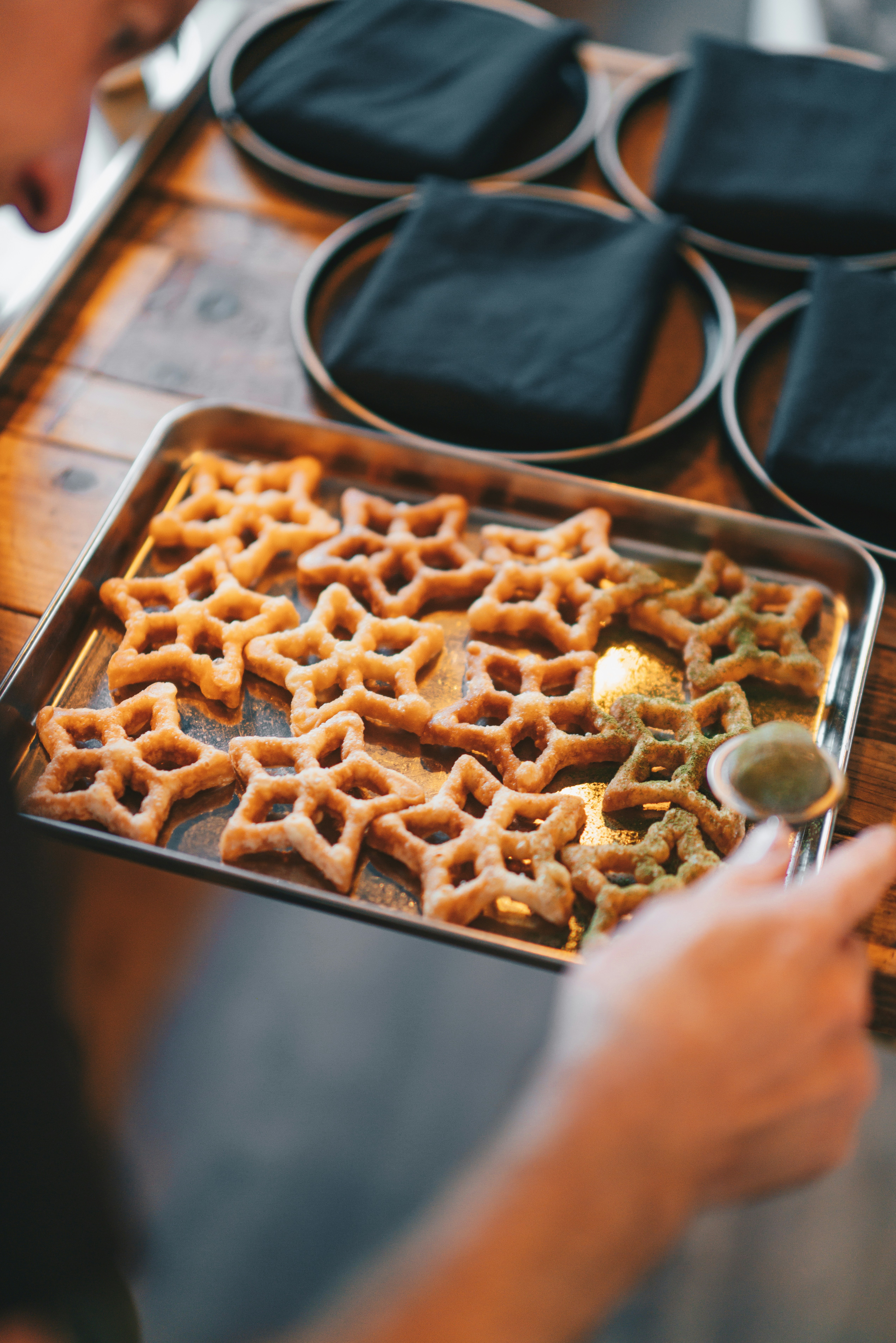 a person holding a spoon over a tray of food