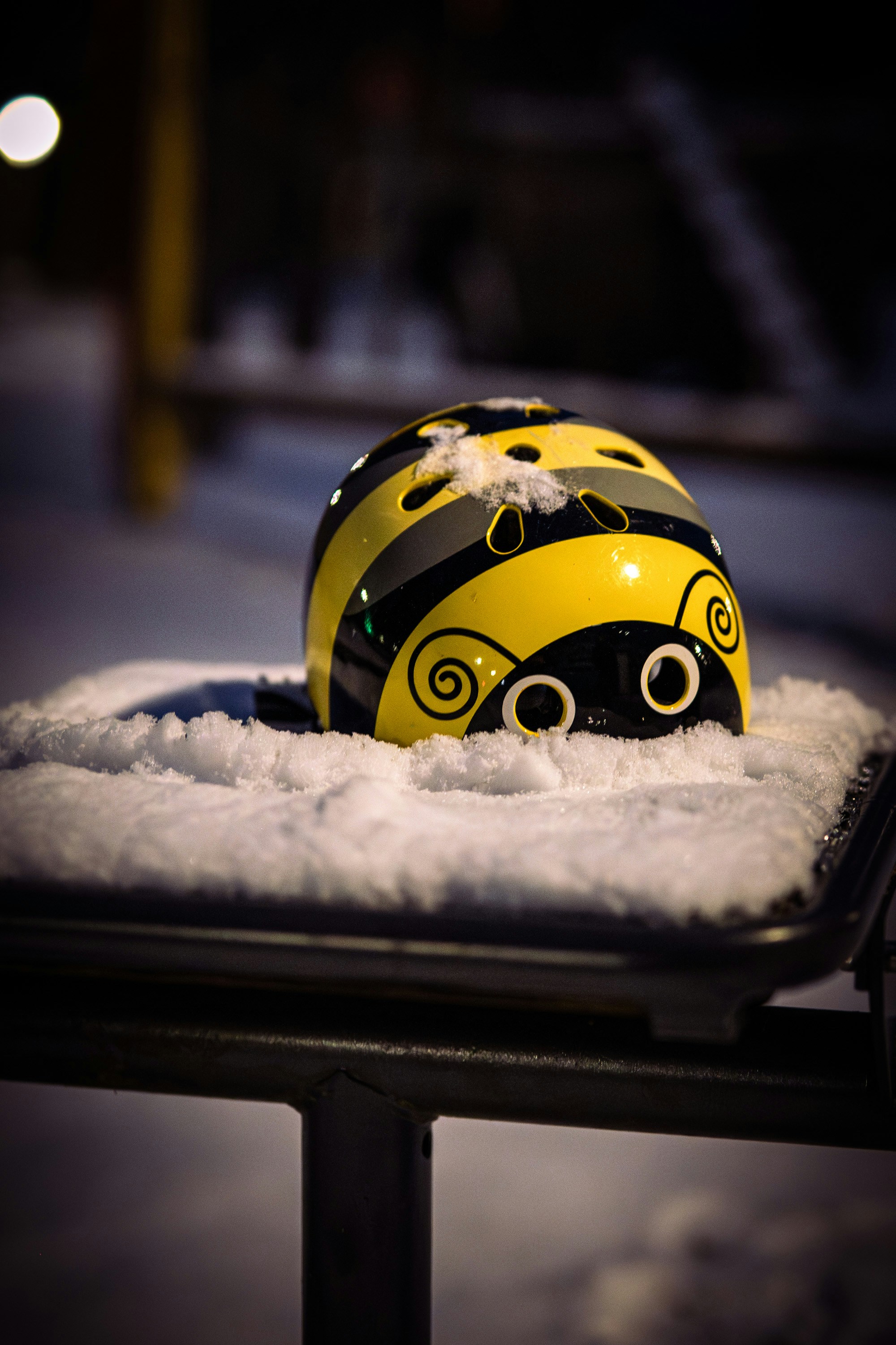 Snow-Capped Cheer: A Yellow-Black Helmet Peaks Through Frosty Rail