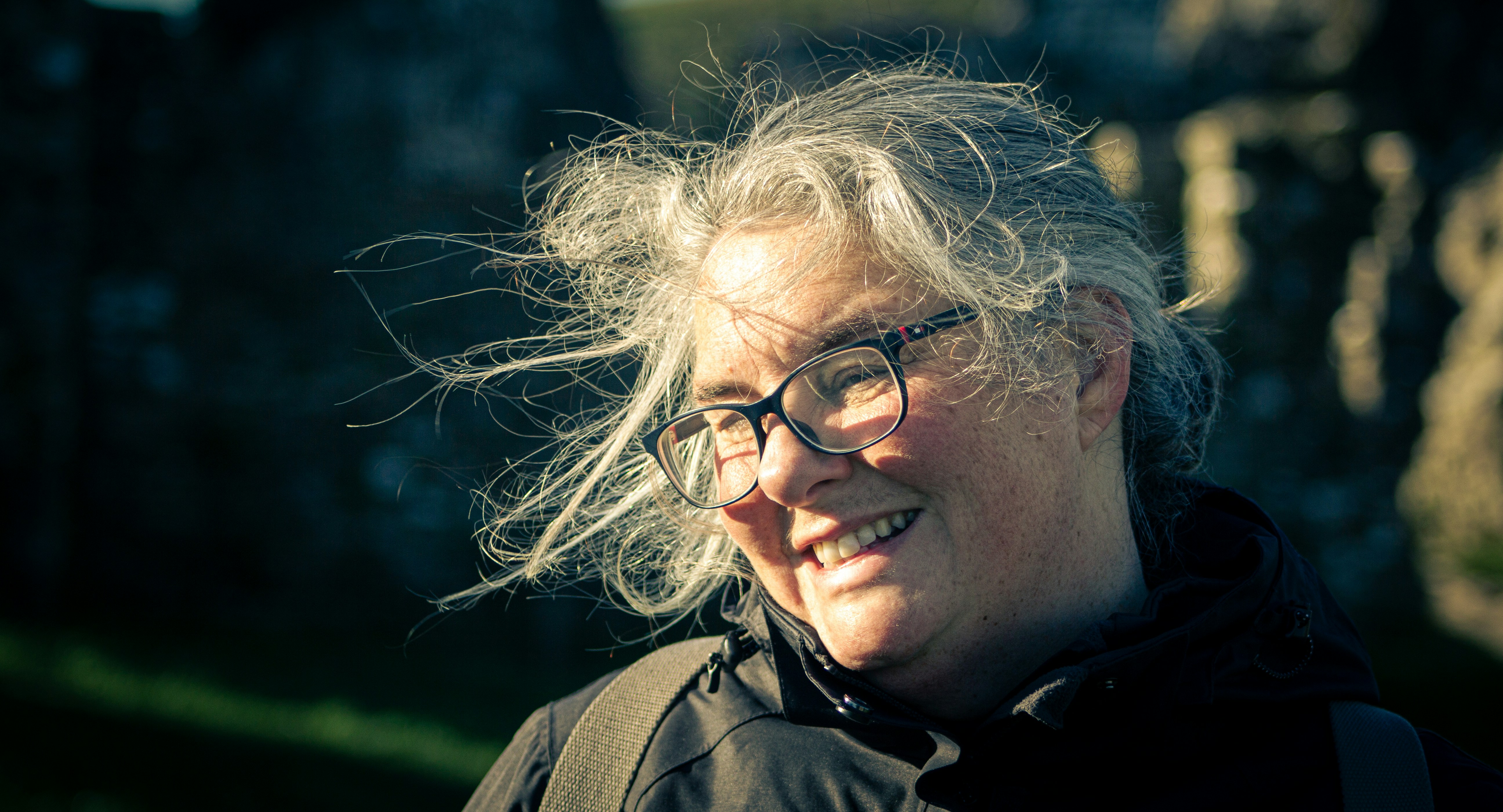 Glimmer in the Breeze: Sunlit Portrait of a Wind-Swept Smile
