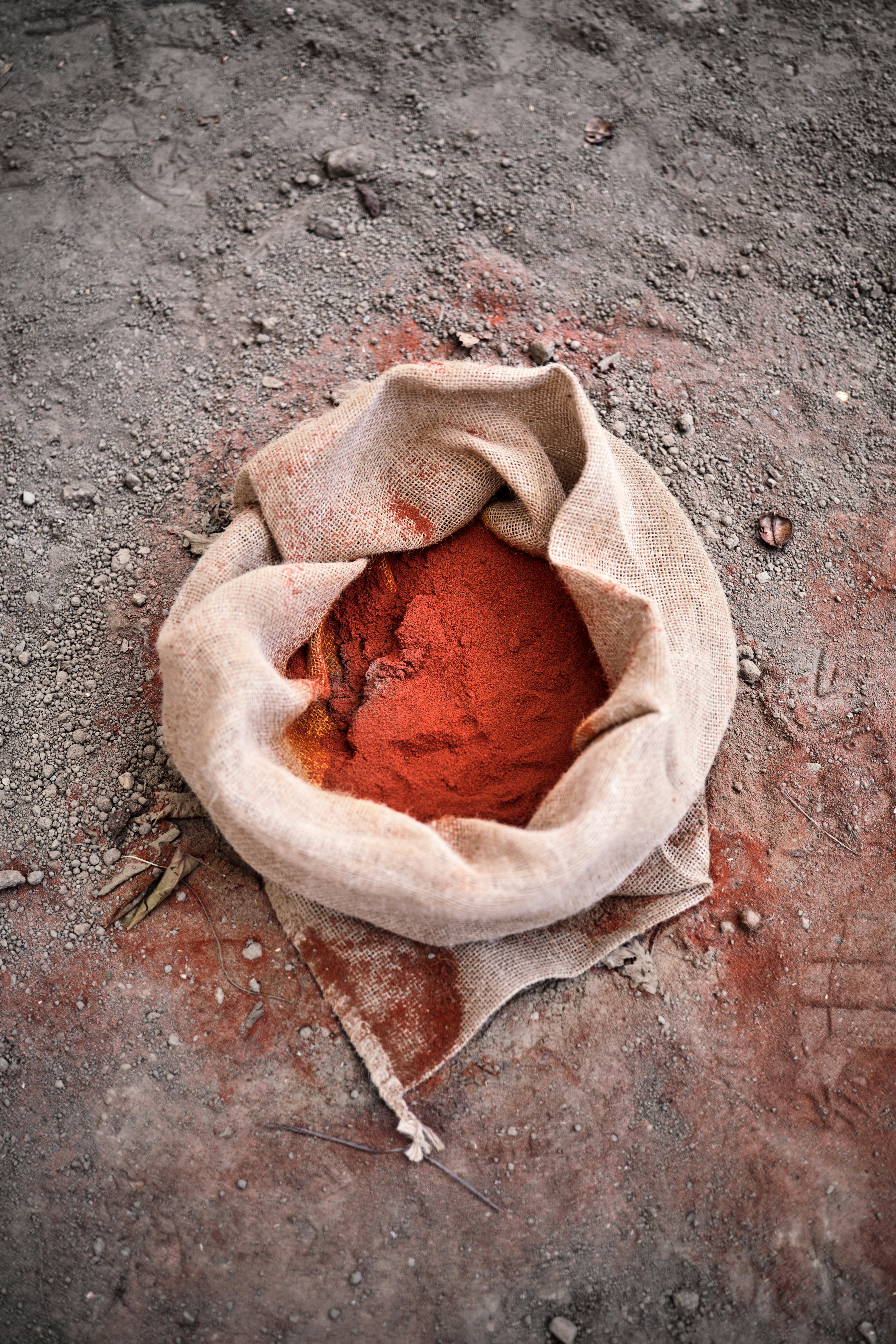 Crimson Pigment in a Burlap Sack: A Quiet Spill on Red Earth