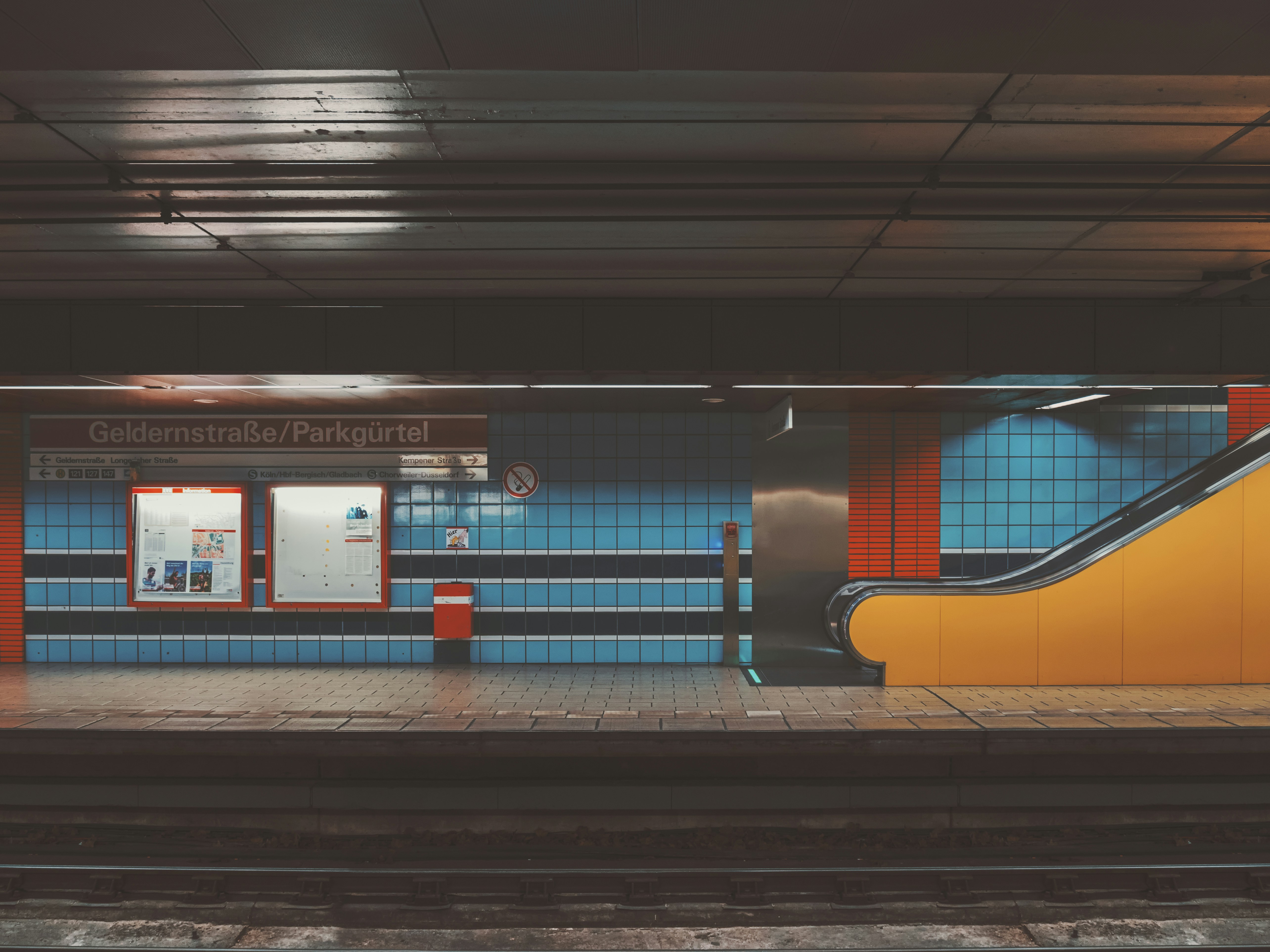 Platform Geometry: Blue Tiles, Orange Escalator, and Quiet Subway Light