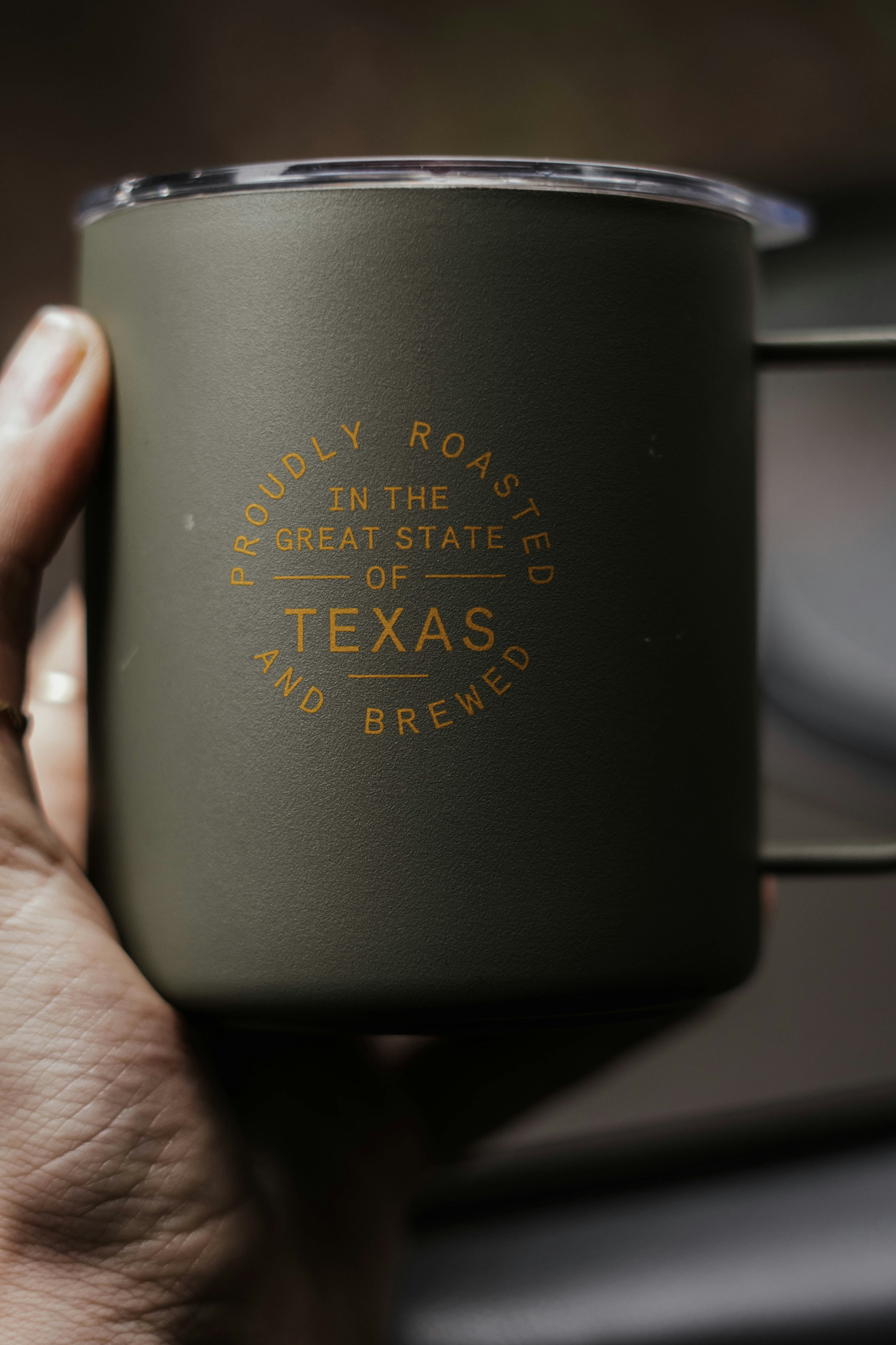 Texas-mug silhouette: a close-up of a matte cup with golden logo in hand