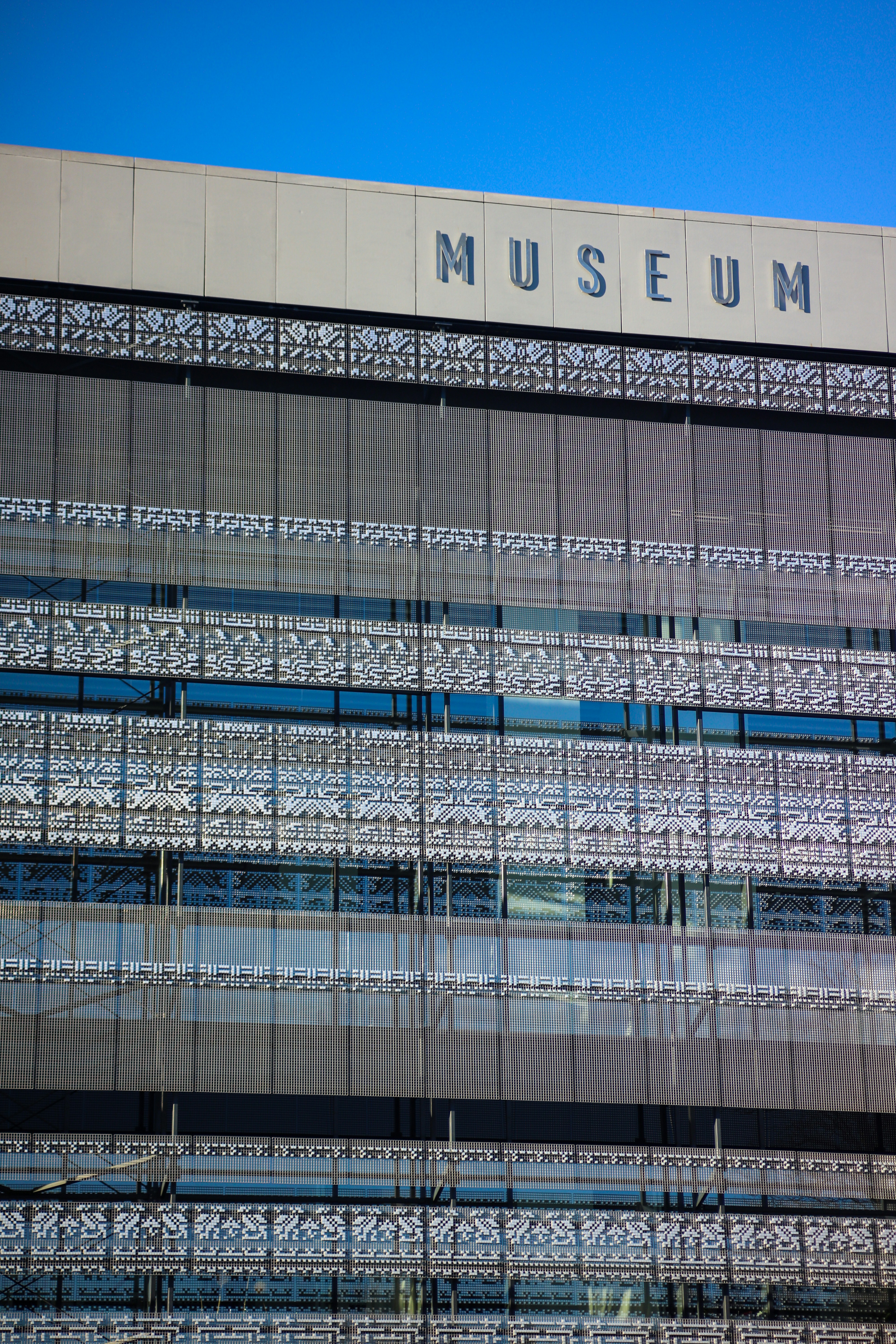 Latticed Rhythm: The Museum Facade under a Clear Blue Sky