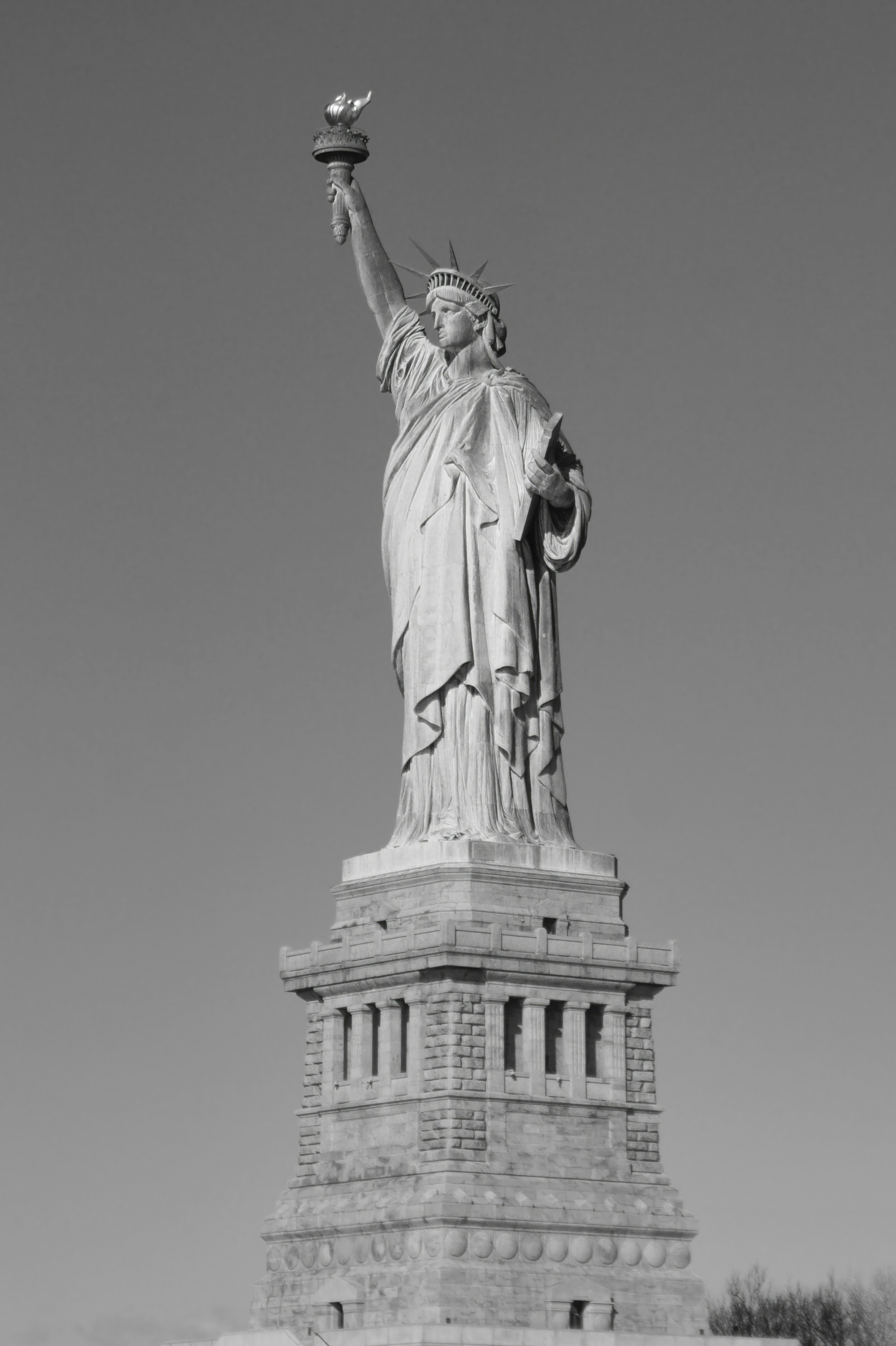 Statue of Liberty rises against a clear sky, captured in monochrome