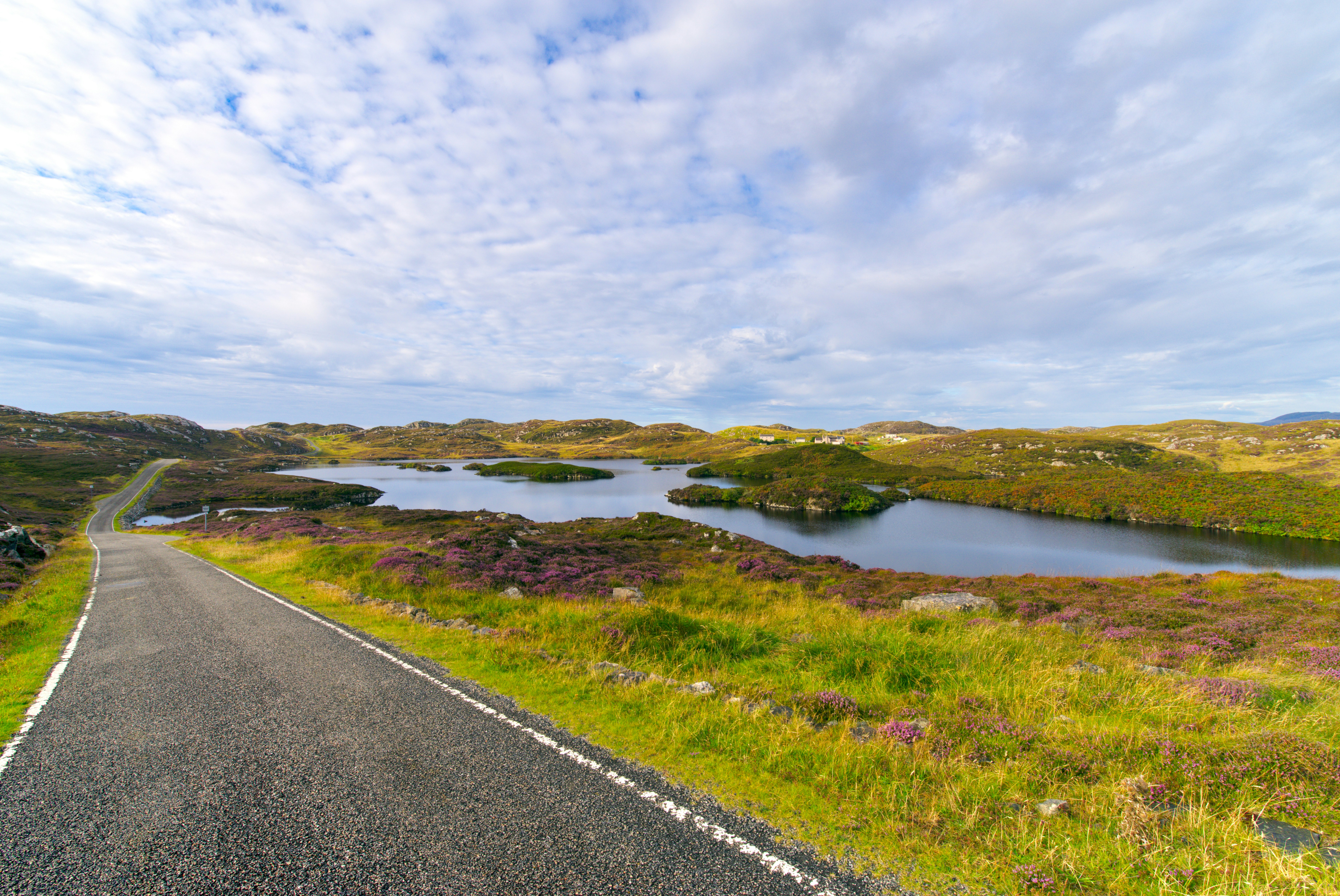 Golden road on Isle of Harris heading south. | a road with a lake in the middle of it