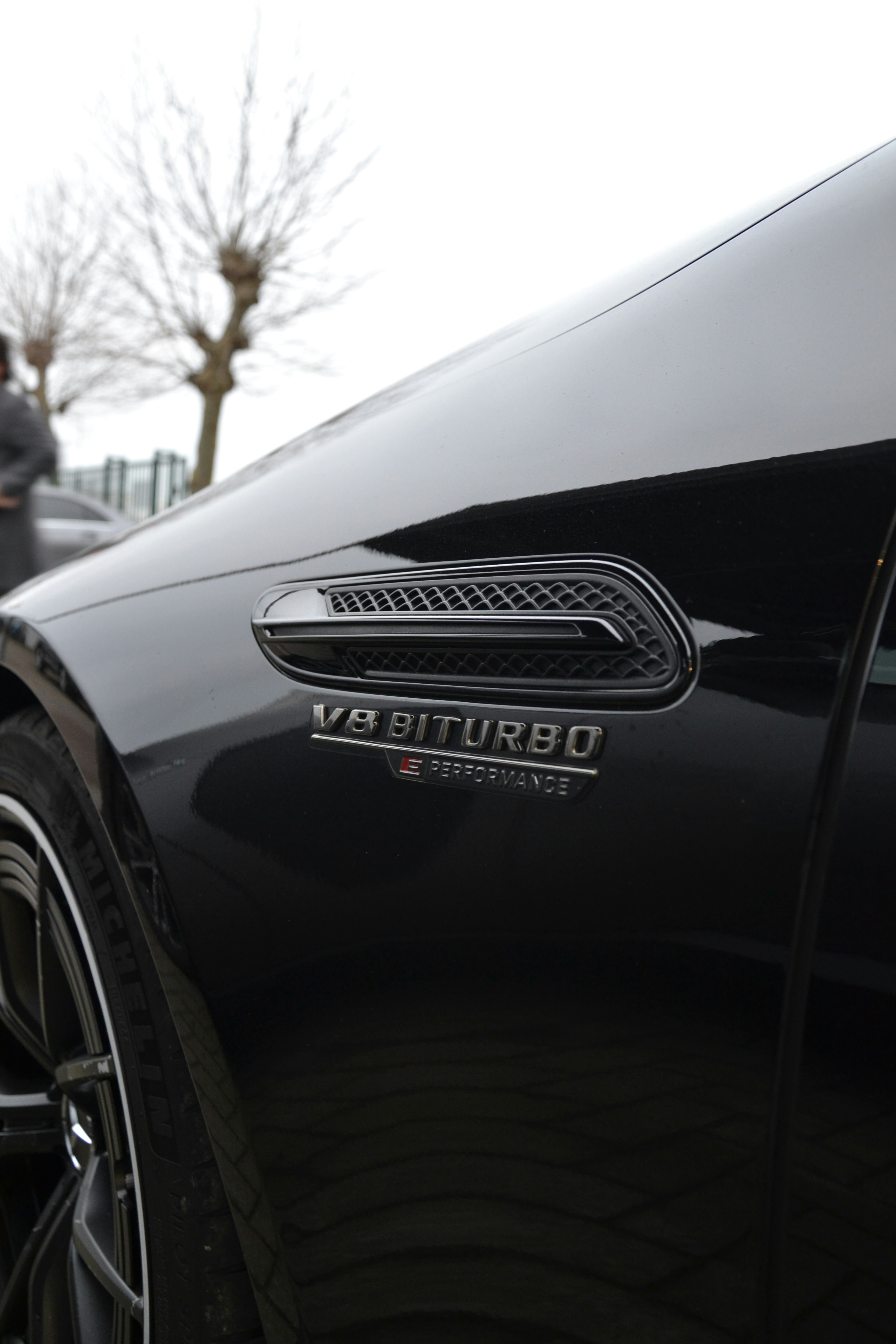 Close-up of a black car's V8 Biturbo emblem with a focus on its aerodynamic design.