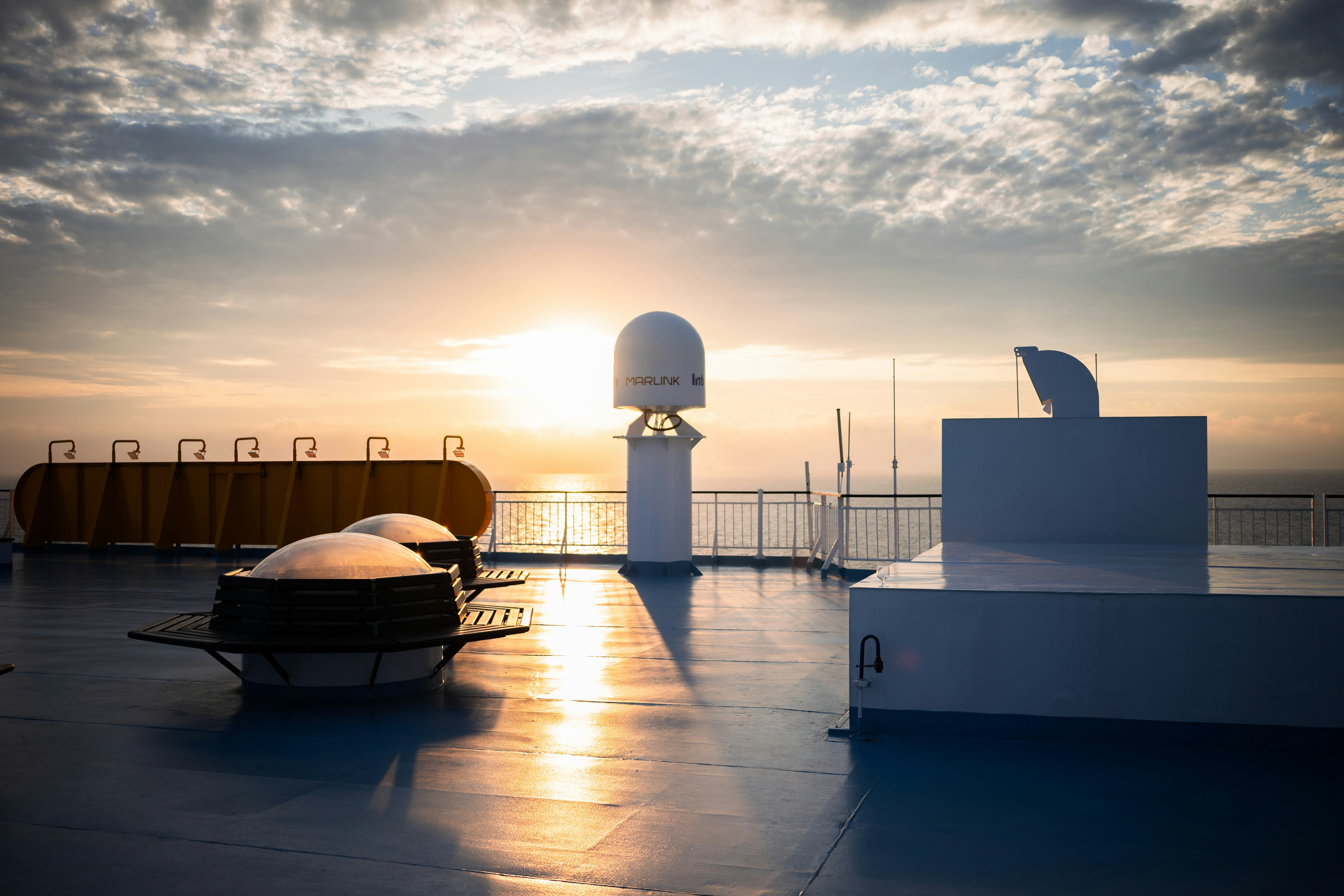 Sunset Over a Vessel's Rooftop: Dome, Vent, and an Azure Deck