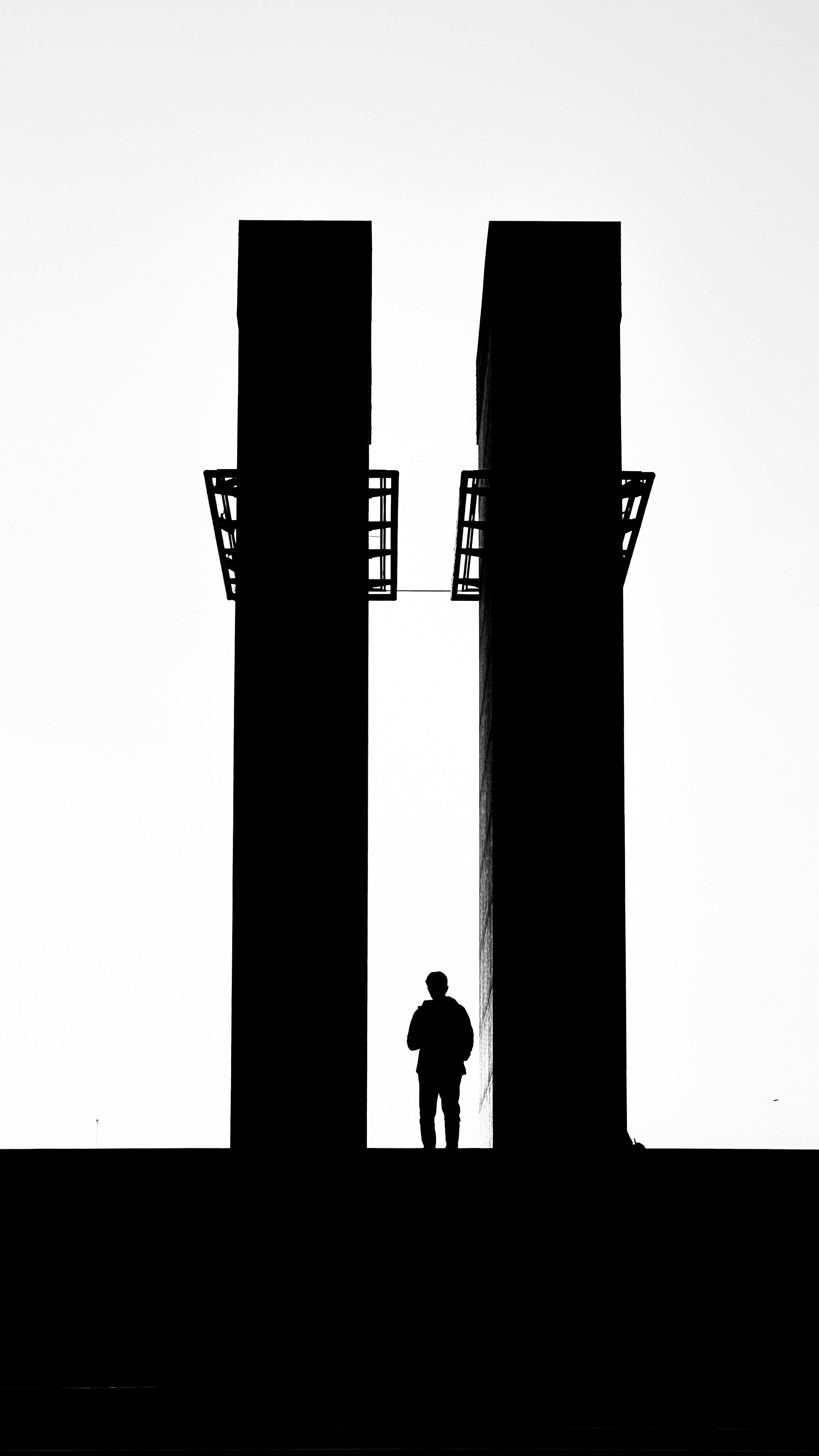 A man standing in between two tall buildings photo – Free Silhouette ...