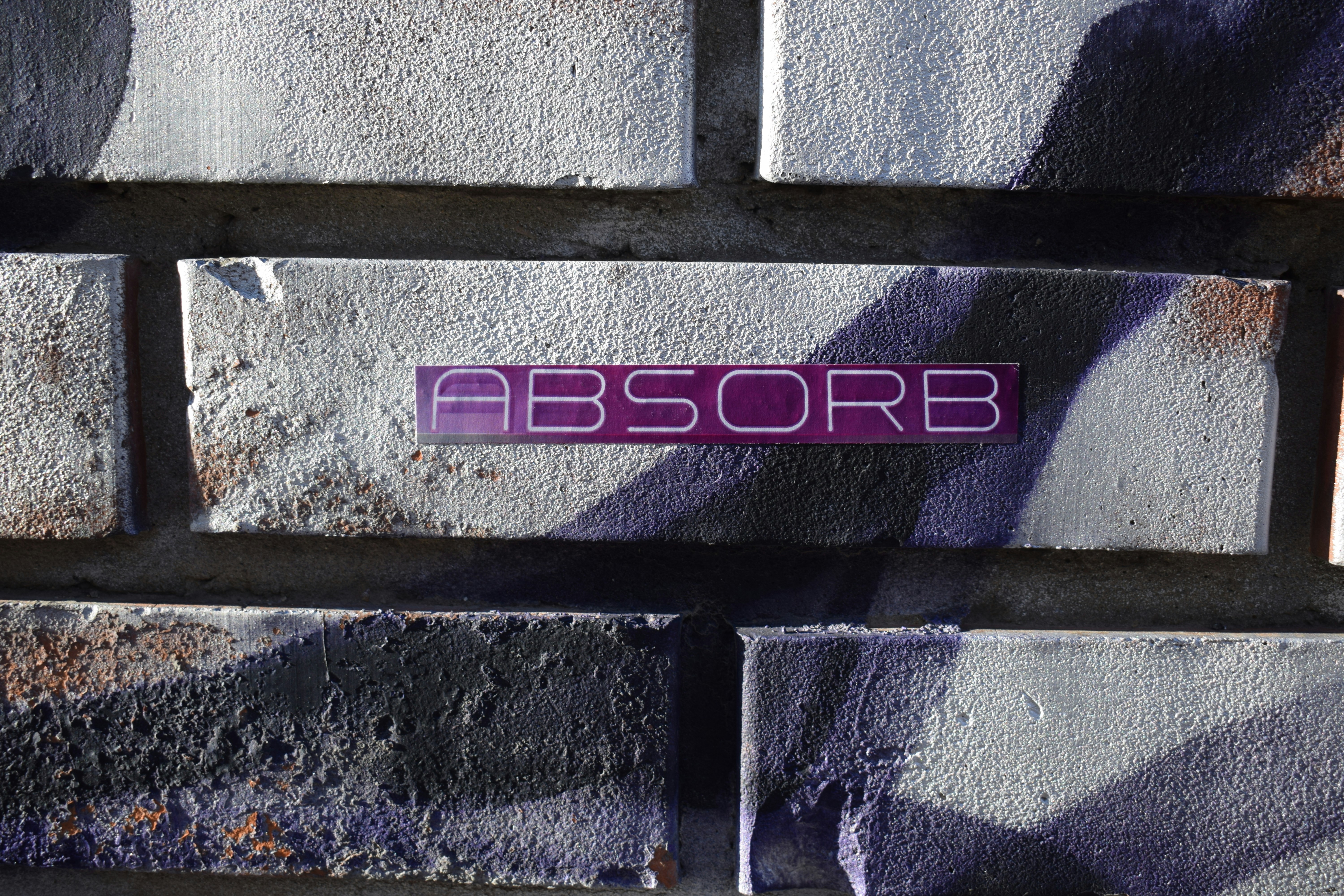 Una pared de ladrillo con un letrero morado foto – Imagen de Gris ...