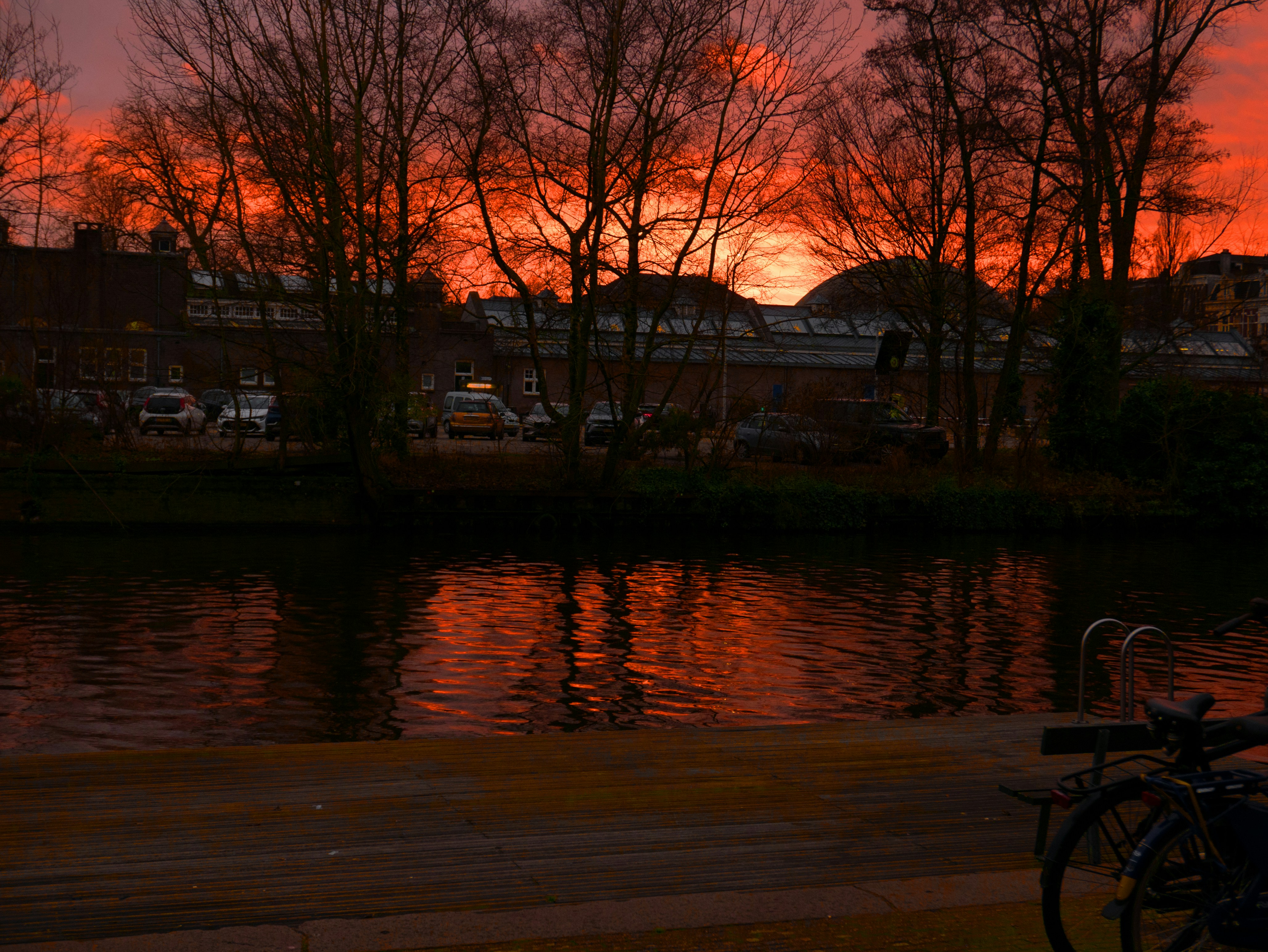 Crimson Dusk over Riverside Silhouettes