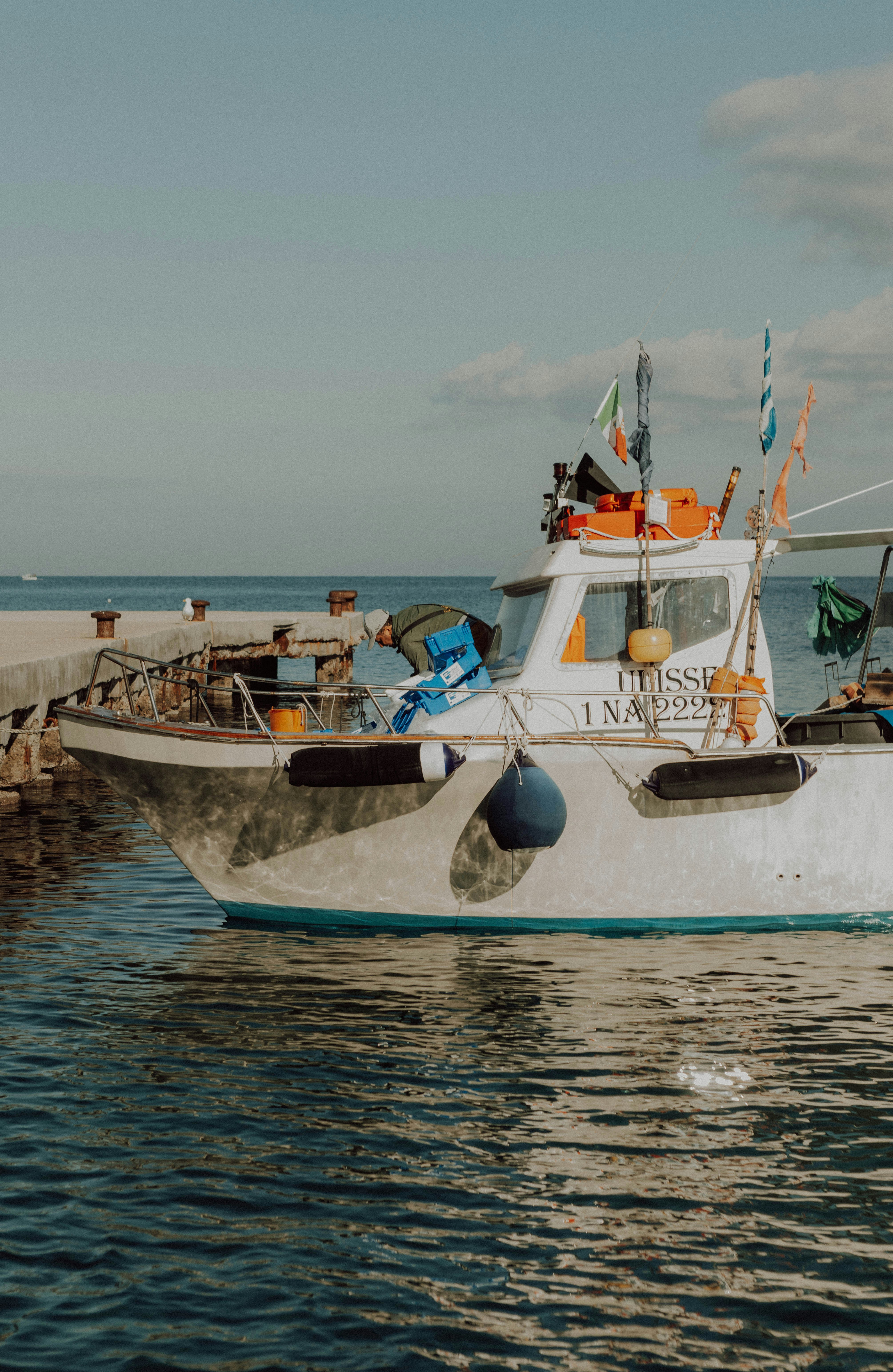 Fishing boat docked beside a weathered pier under a clear sky.