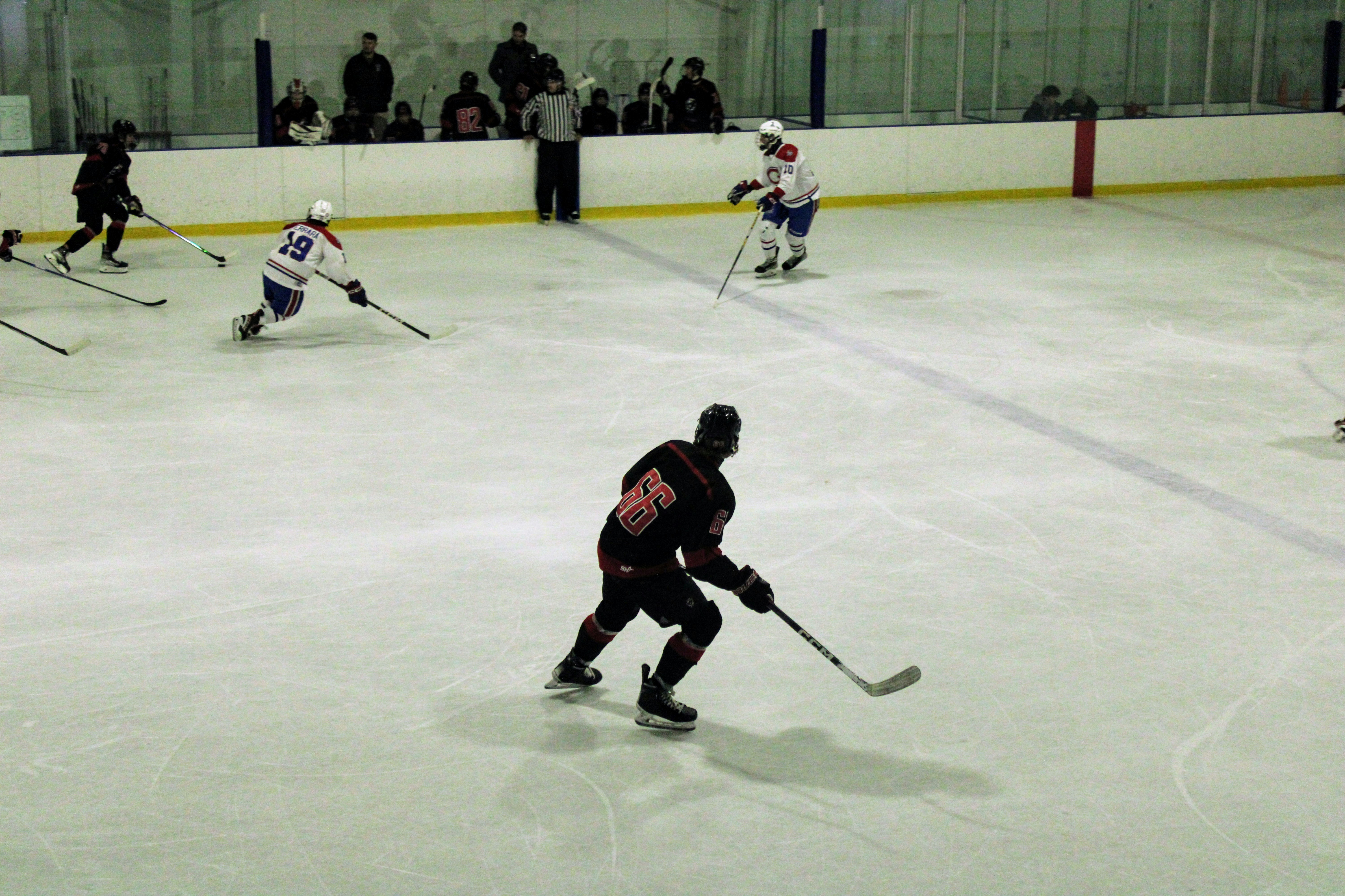 Breakaway on Ice: A lone black-jersey skater charges the play under rink glare