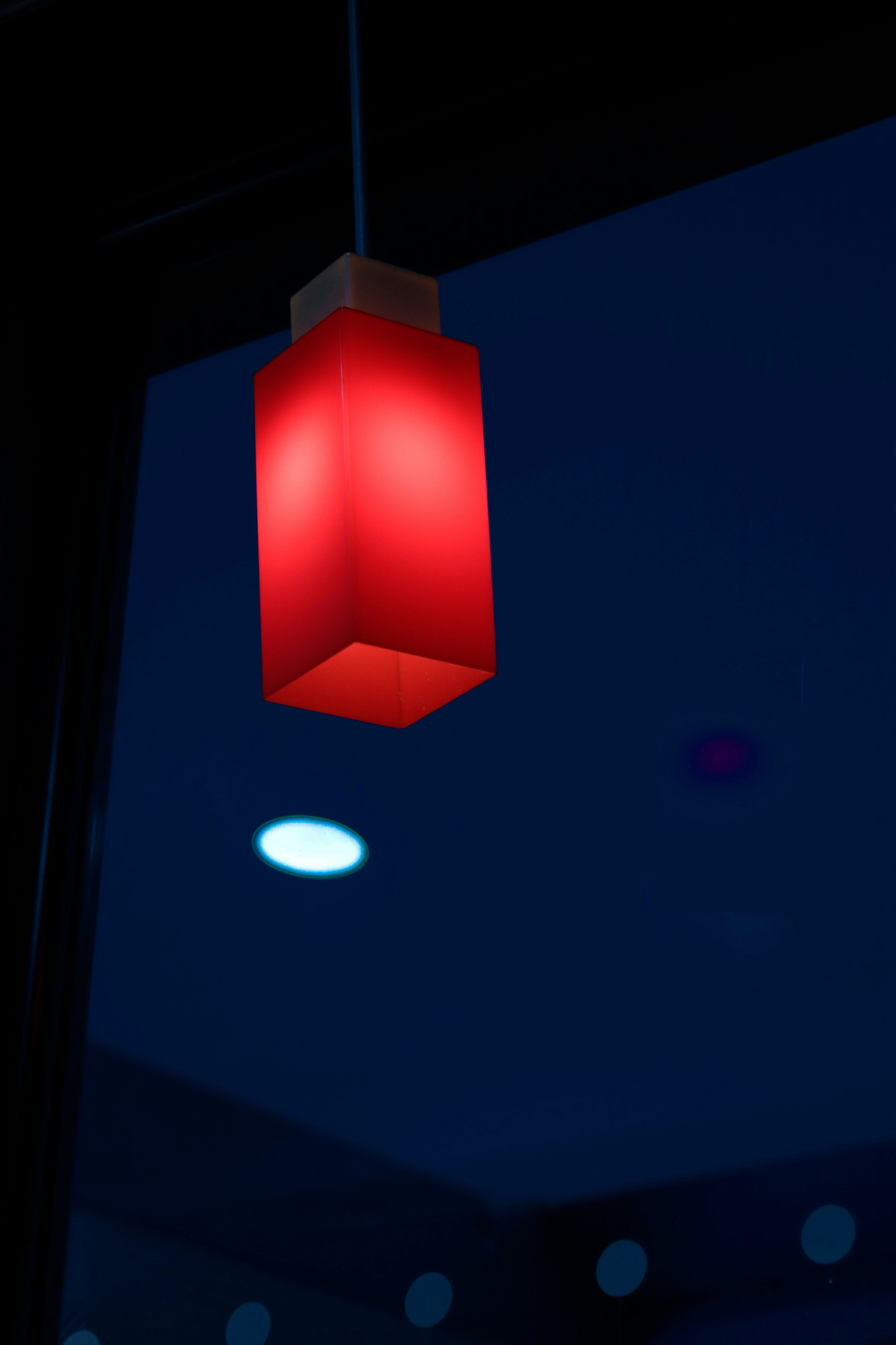Crimson Pendant Lantern Casting Warmth Across a Deep Blue Interior