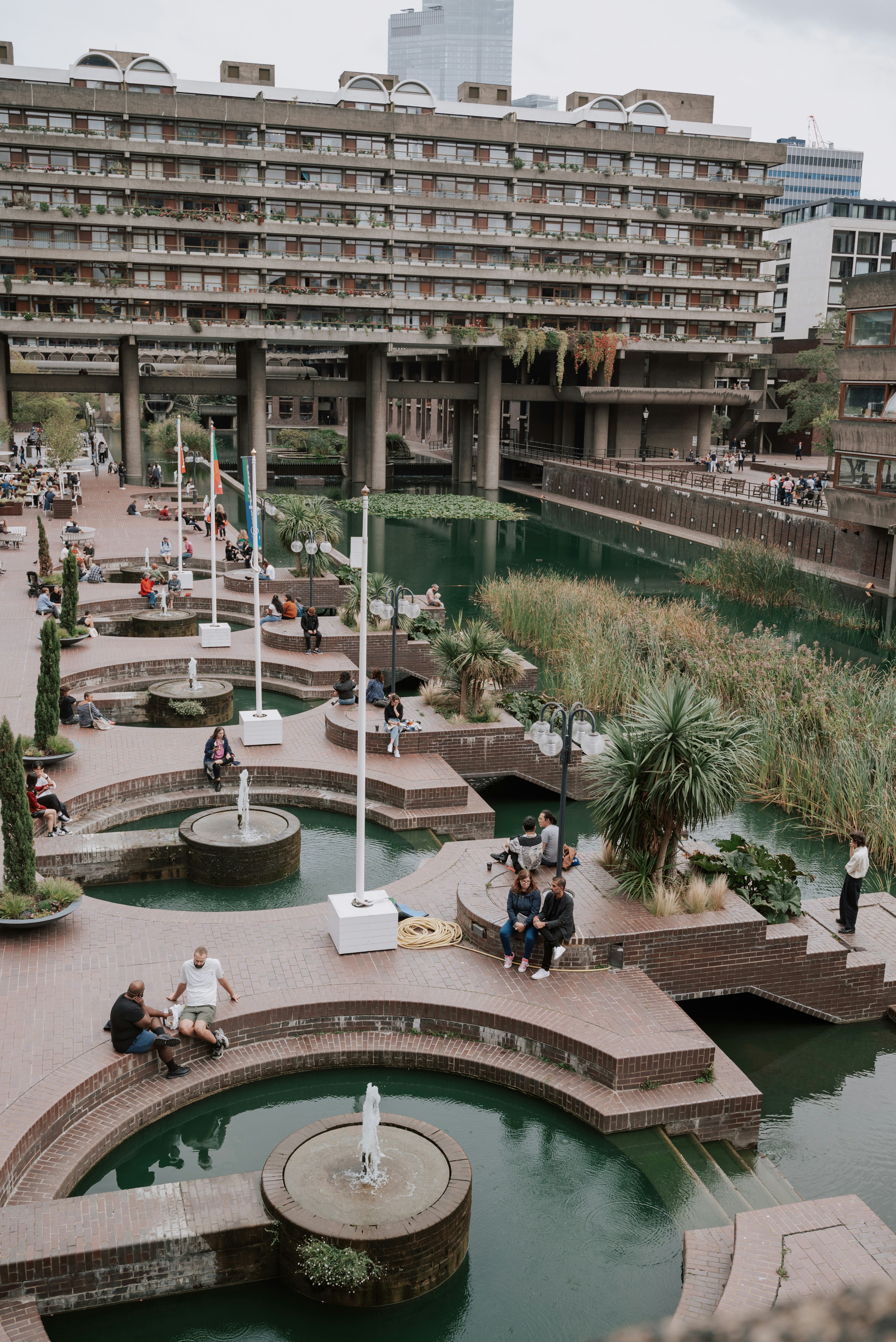 Lush greenery and tranquil water features create a peaceful atmosphere in a bustling urban setting, inviting visitors to relax and unwind.