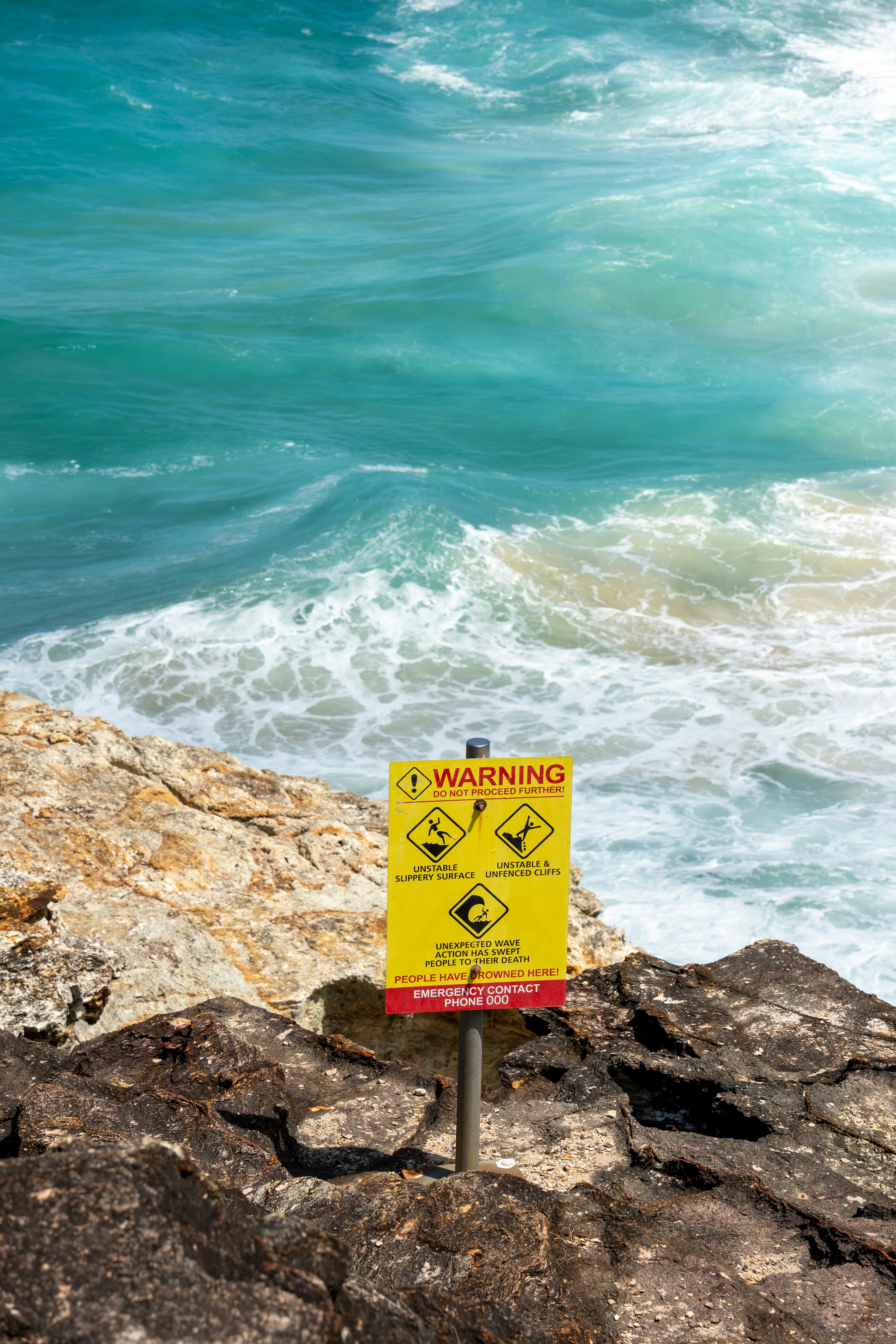 Warning Sign at the Edge: A Seascape of Rocks and Lip of Wave