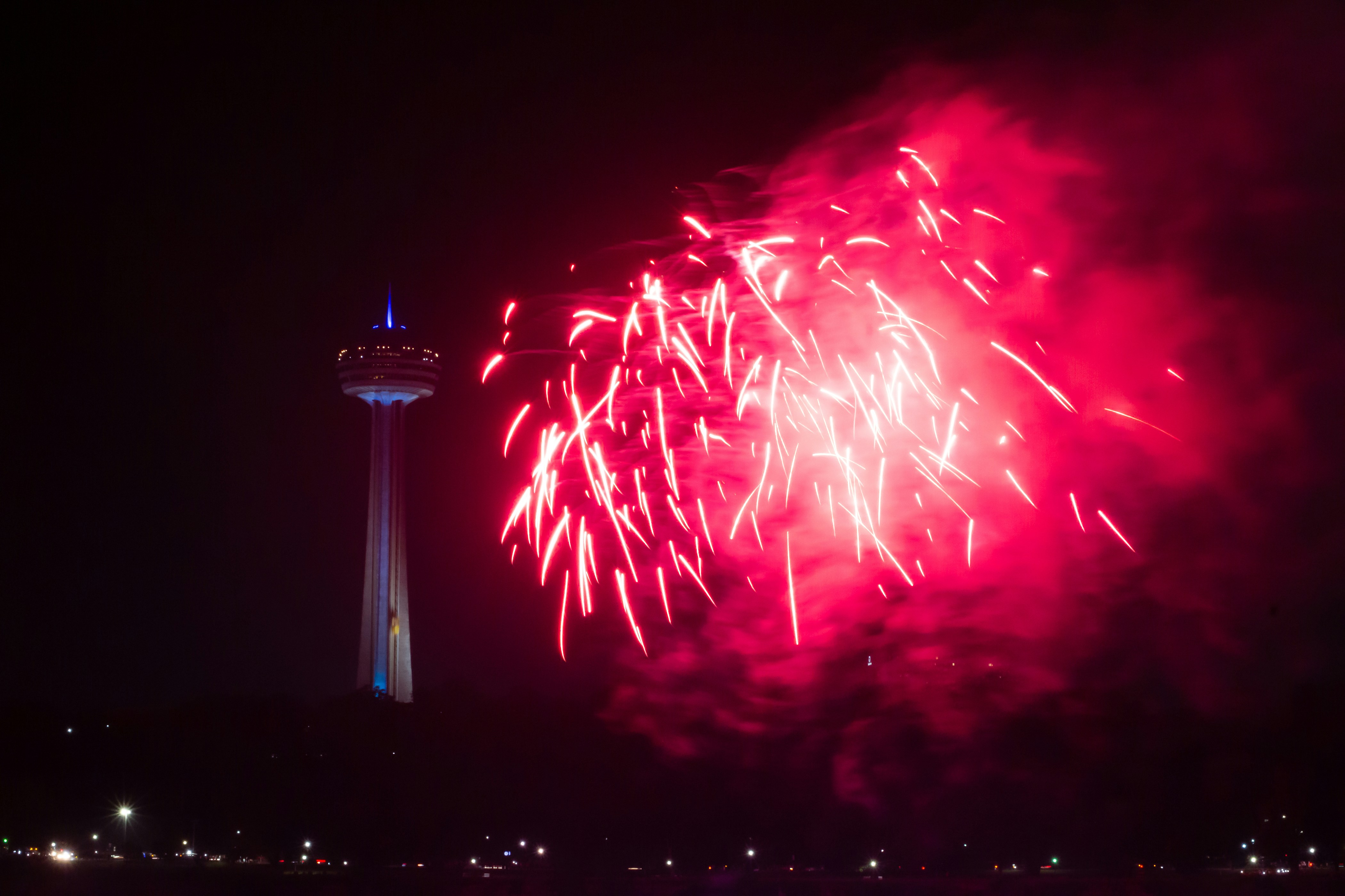 Crimson Burst Over a Silent Skyline: Fireworks Beside the Tower