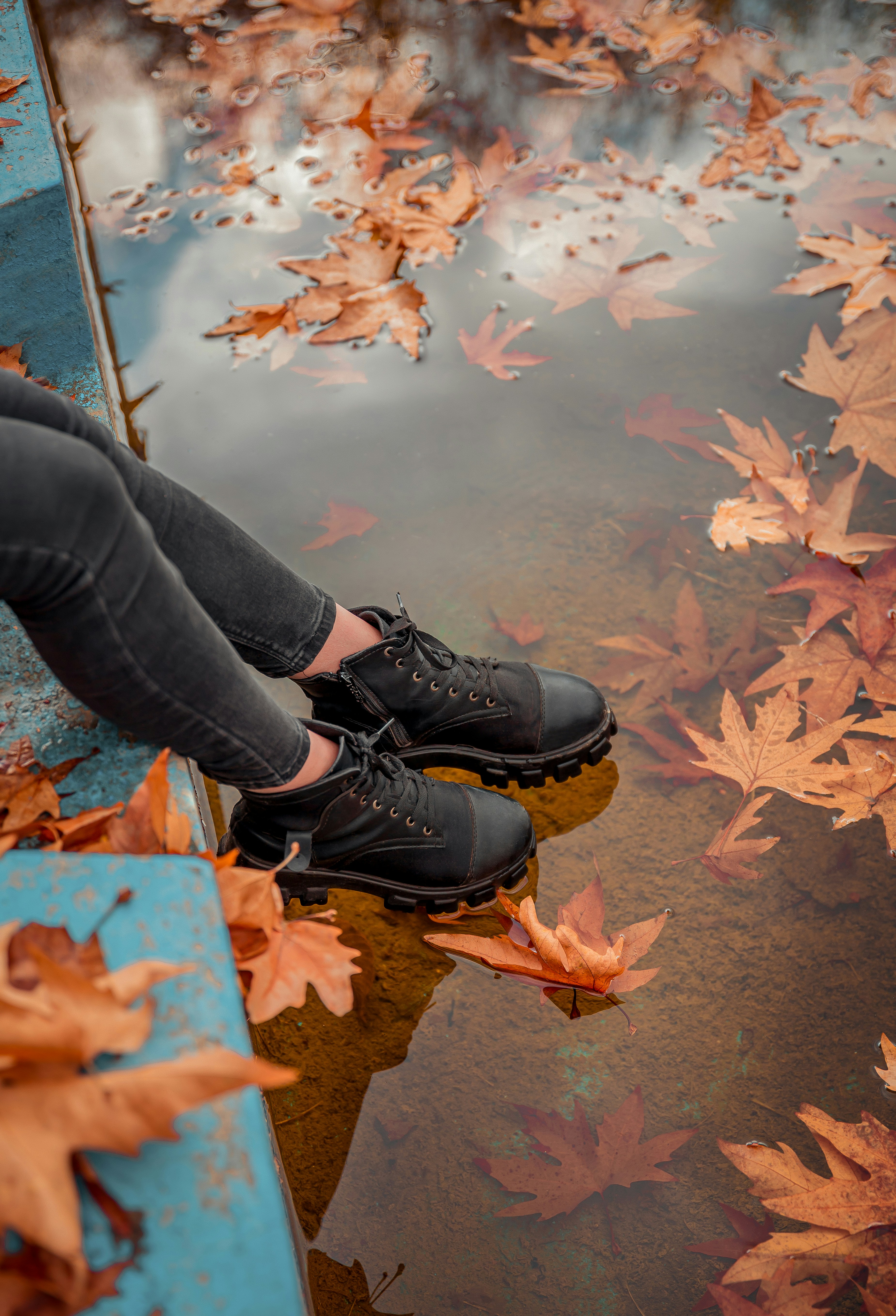 Autumn Reflections: Boots Dip Over a Calm, Leaf-Speckled Pool