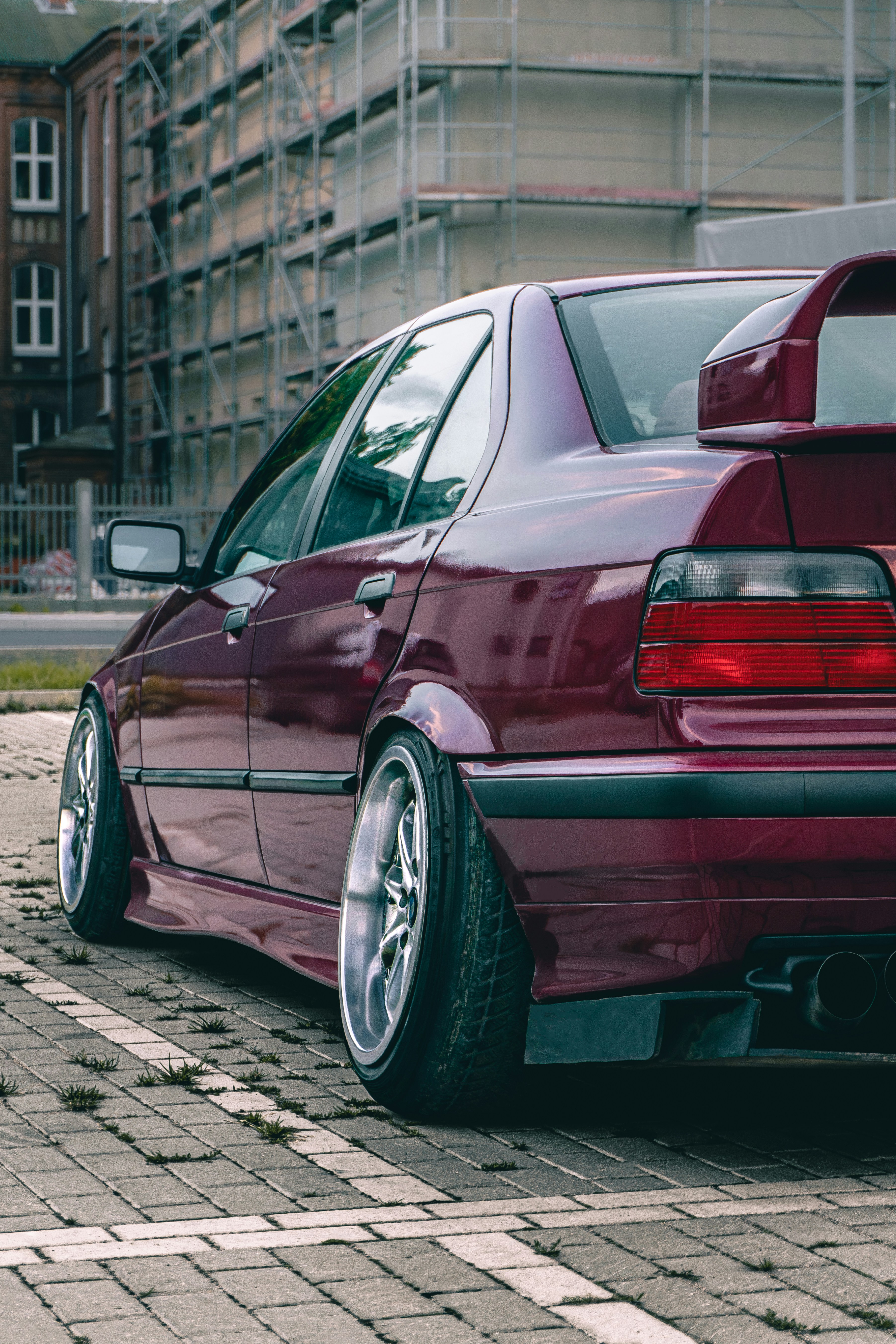 Low Profile Burgundy: Street-Ready Stance Beneath a City Scaffold