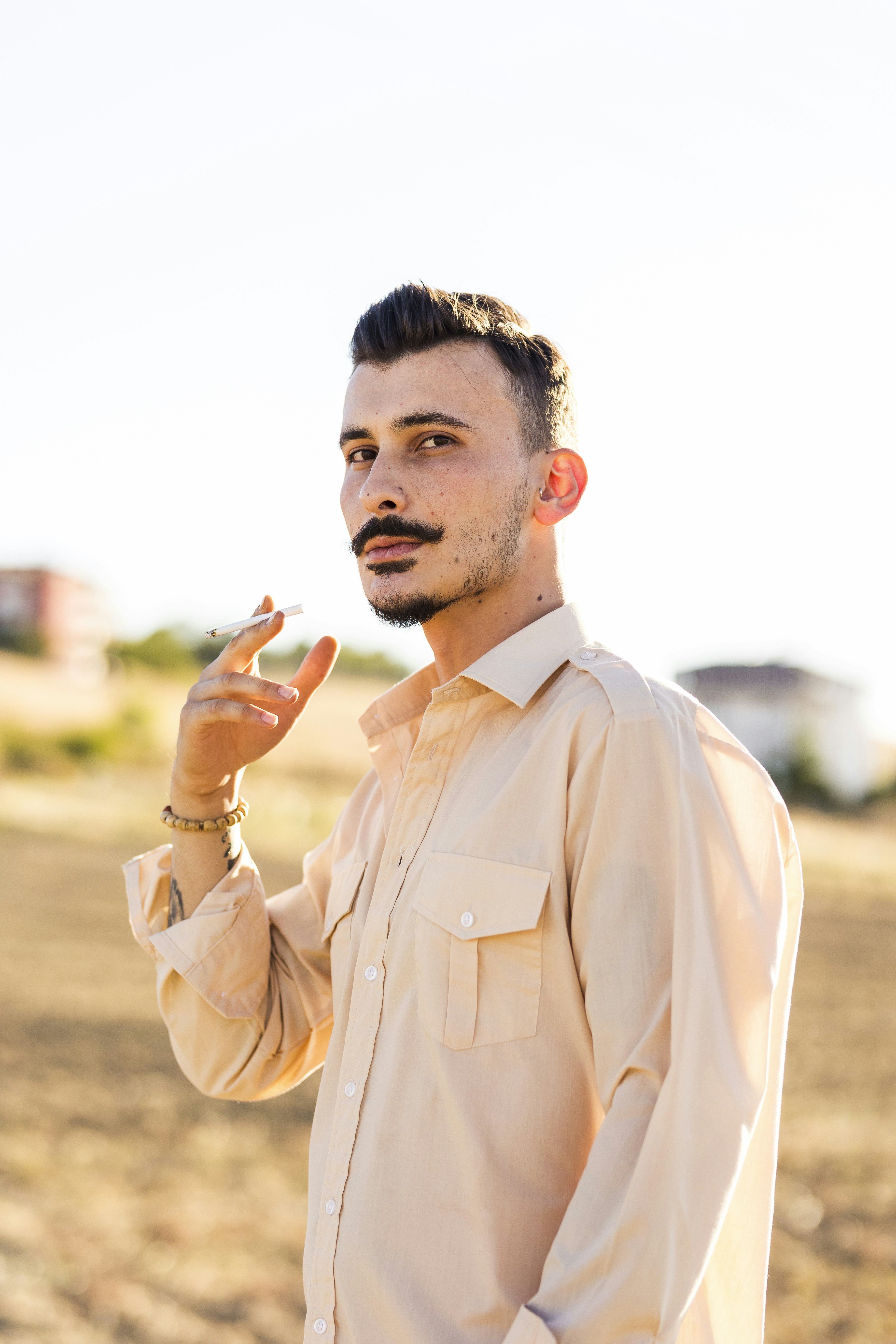 A man standing in a field smoking a cigarette photo – Free Portrait ...