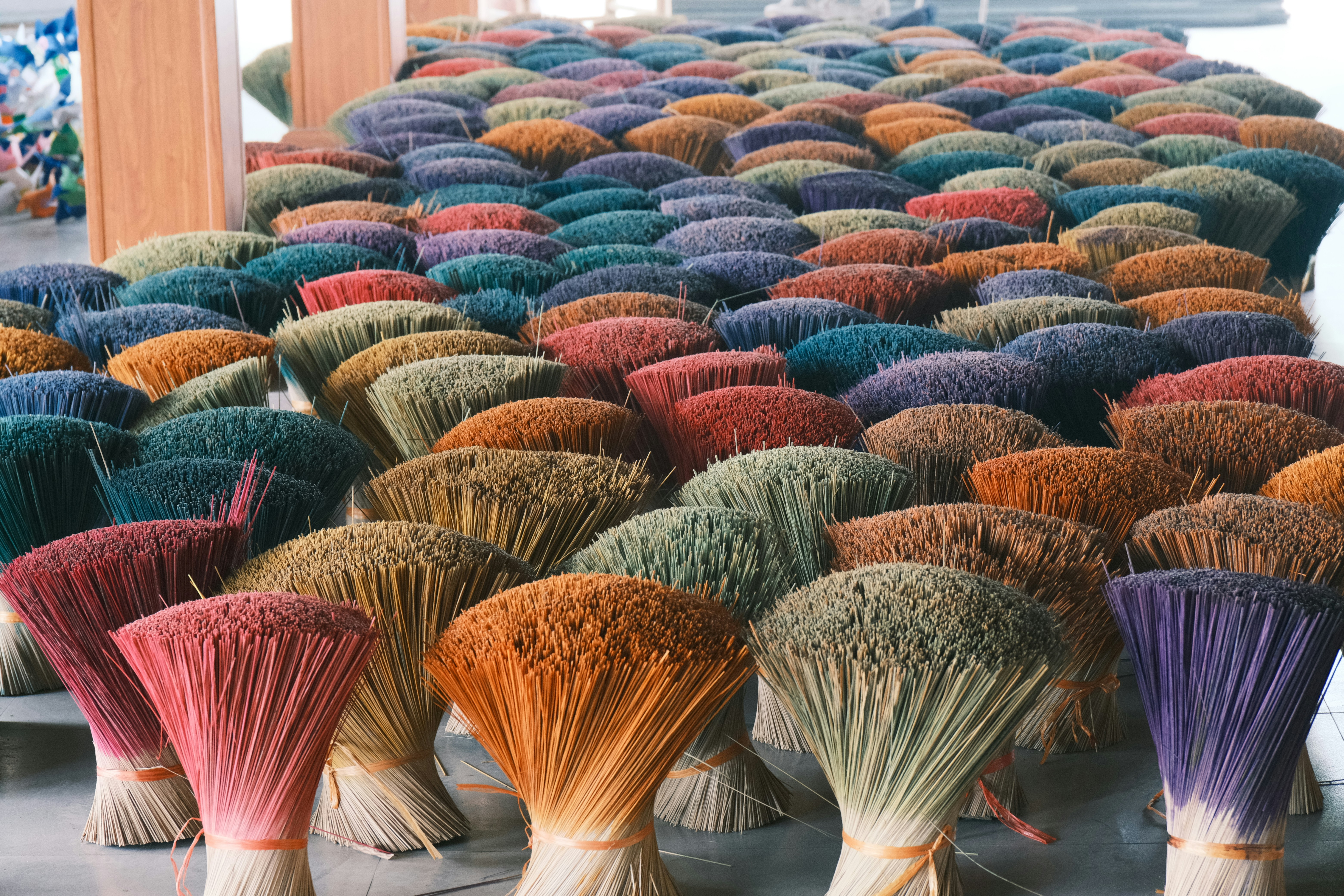 Rainbow Bristle Field: Rows of colorful broom heads line a workshop table