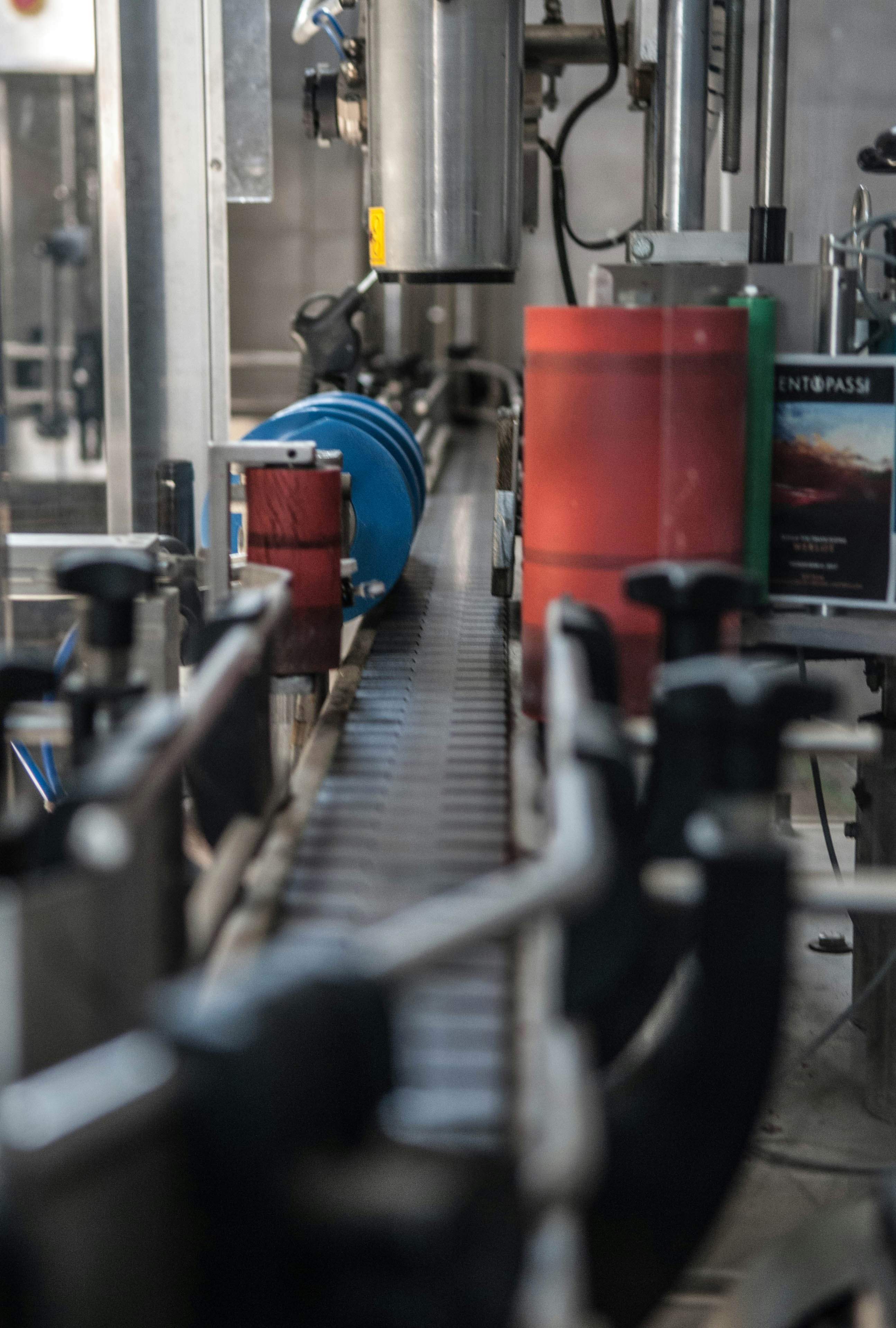 Conveyor belt in a factory setting with machinery and containers in focus.