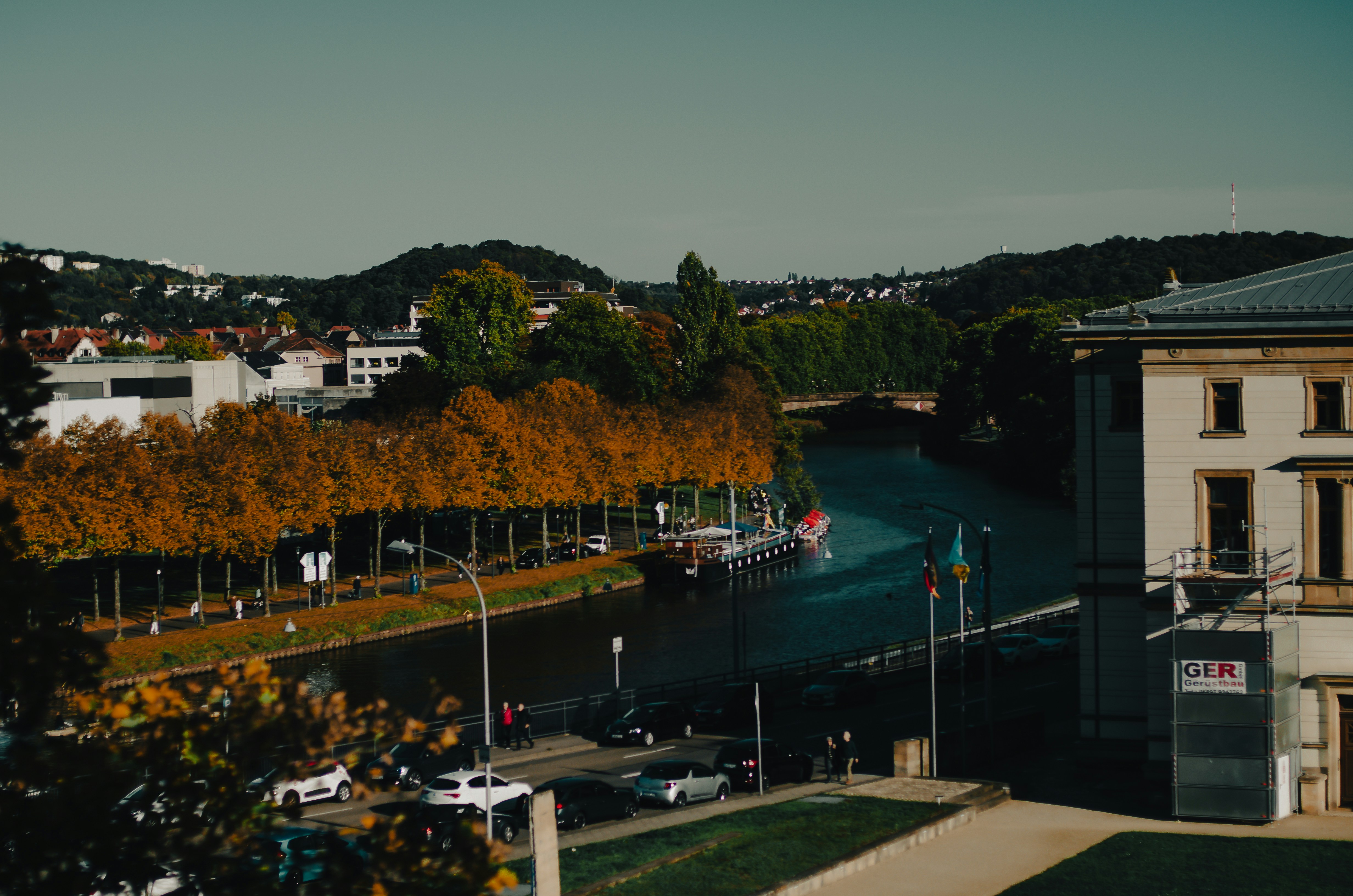 Sunlit River Corridor with Autumn Trees Framing a Cityscape