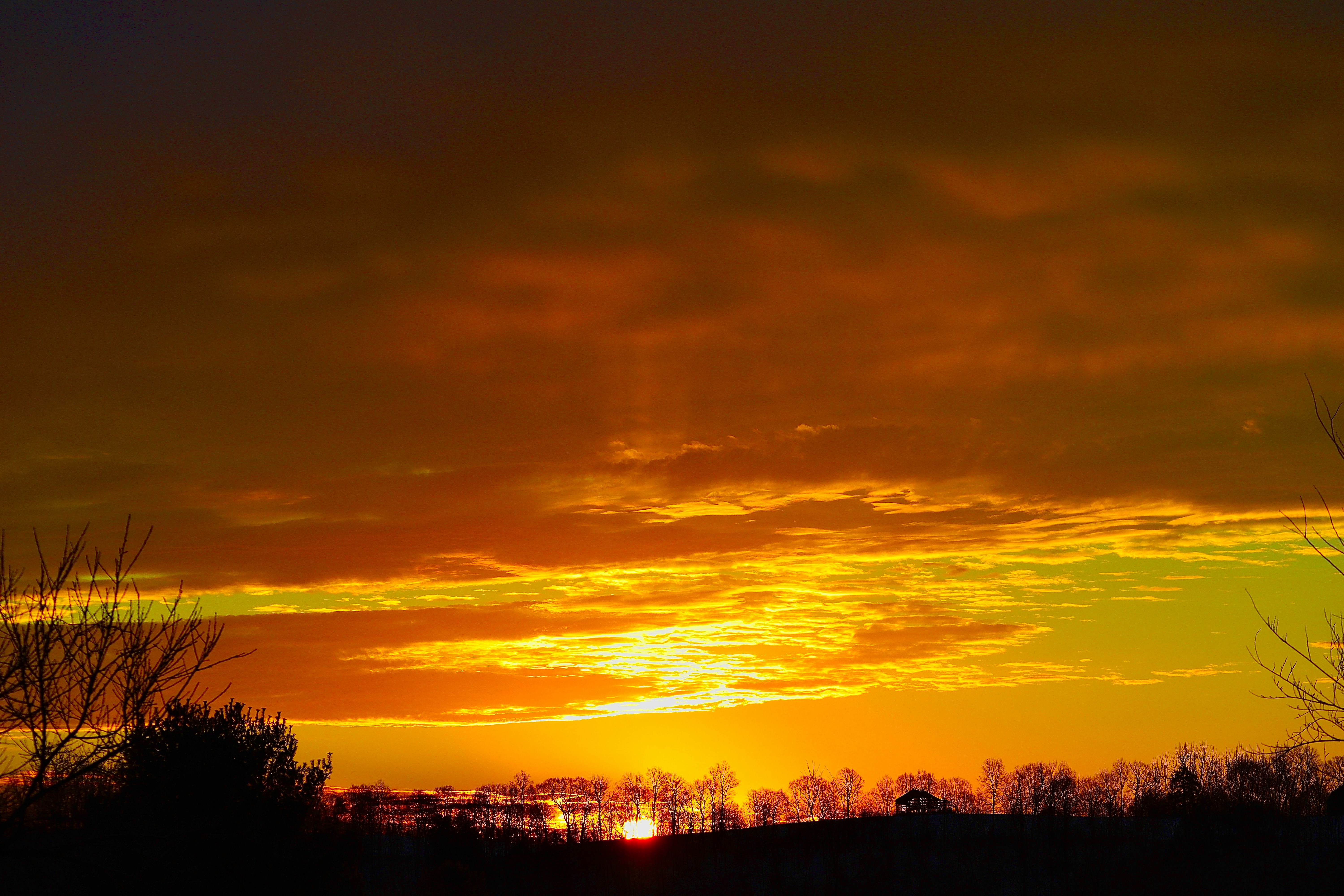 The sun is setting over the trees and hills photo – Free Sunset Image ...