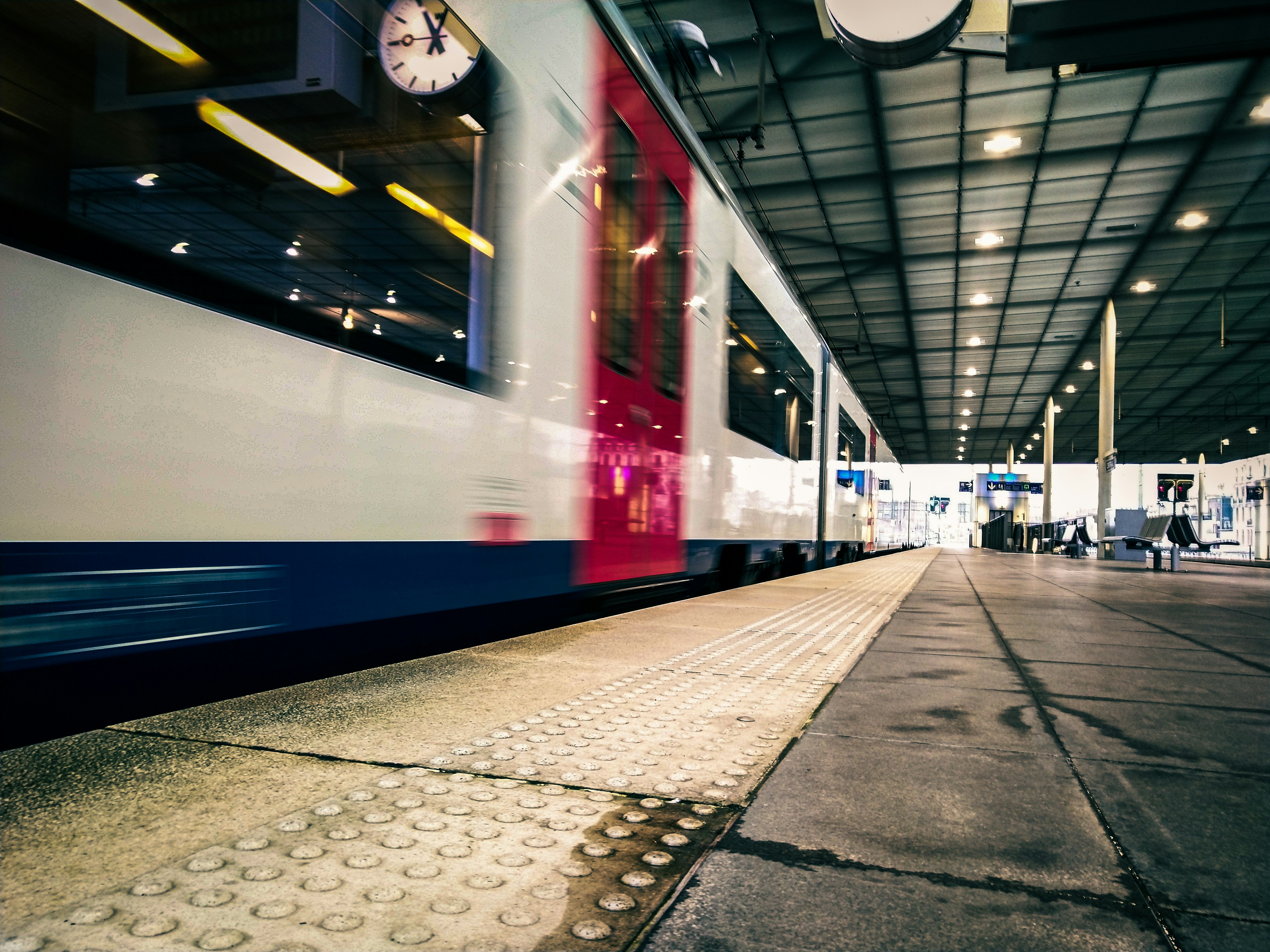 Un train passant devant une gare à côté d’un quai photo – Photo ...