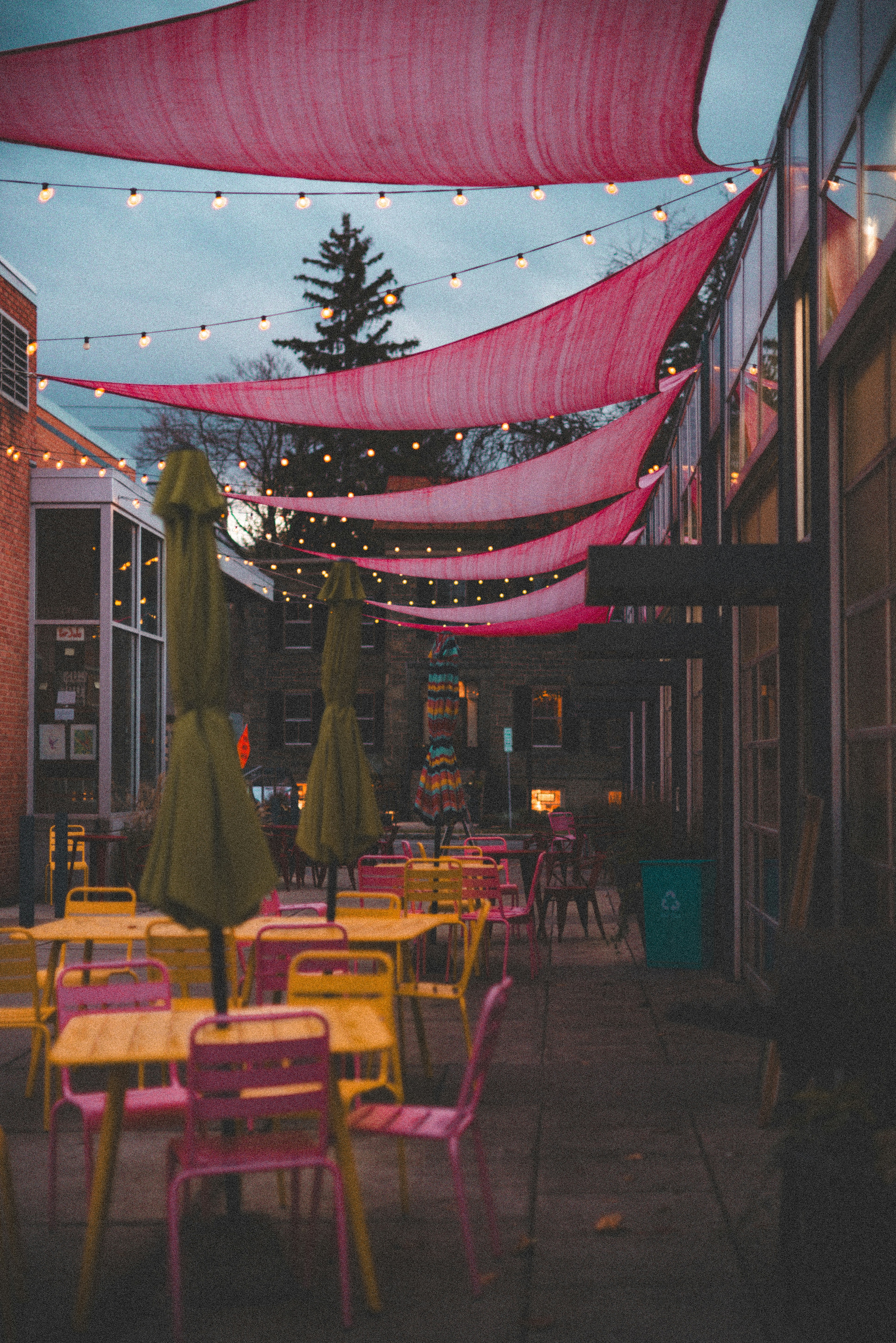 Colorful Bistro Courtyard Under Coral Fabric Canopies at Dusk