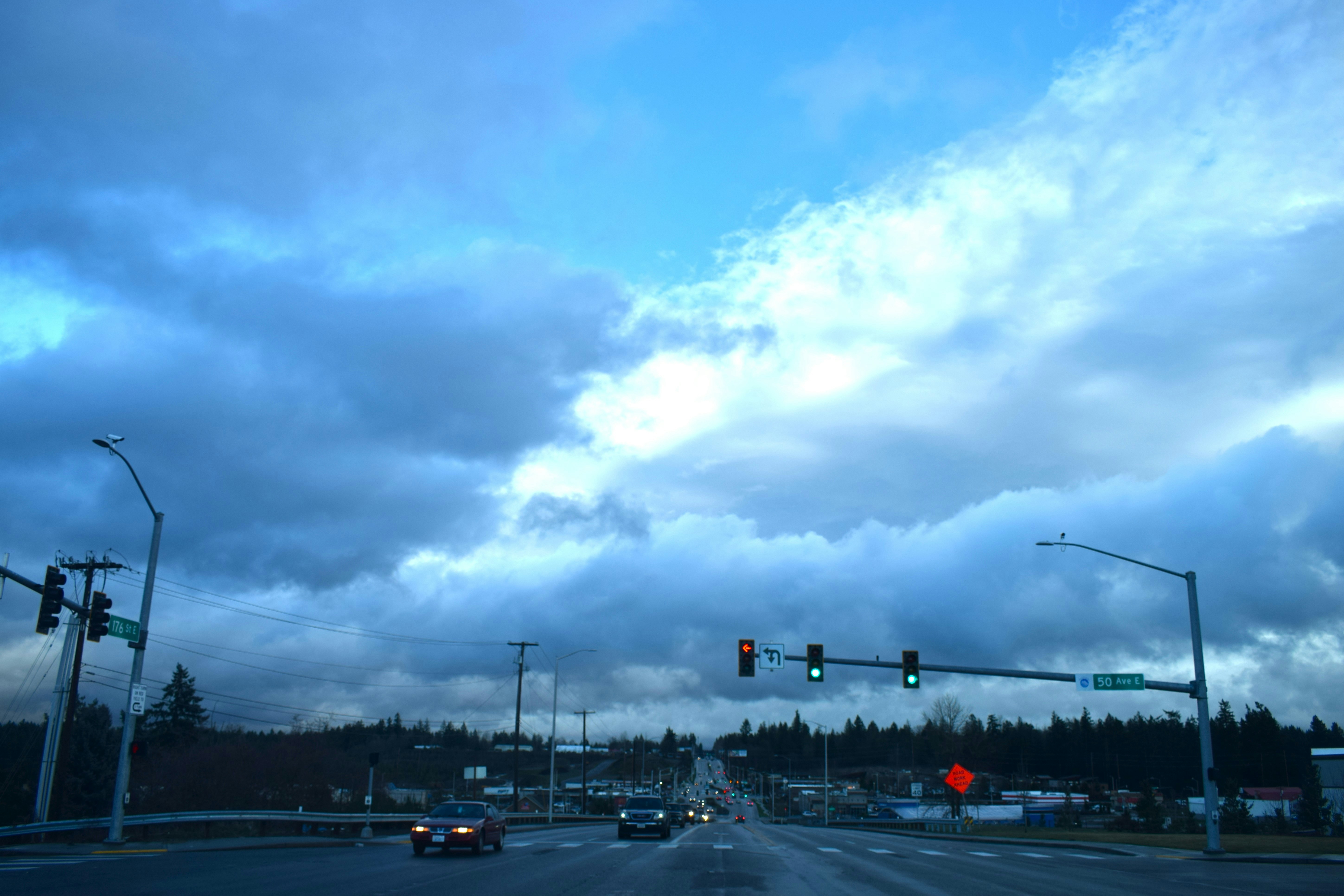 Red Light at the Horizon: A Quiet Highway Under a Cloud-Scattered Sky