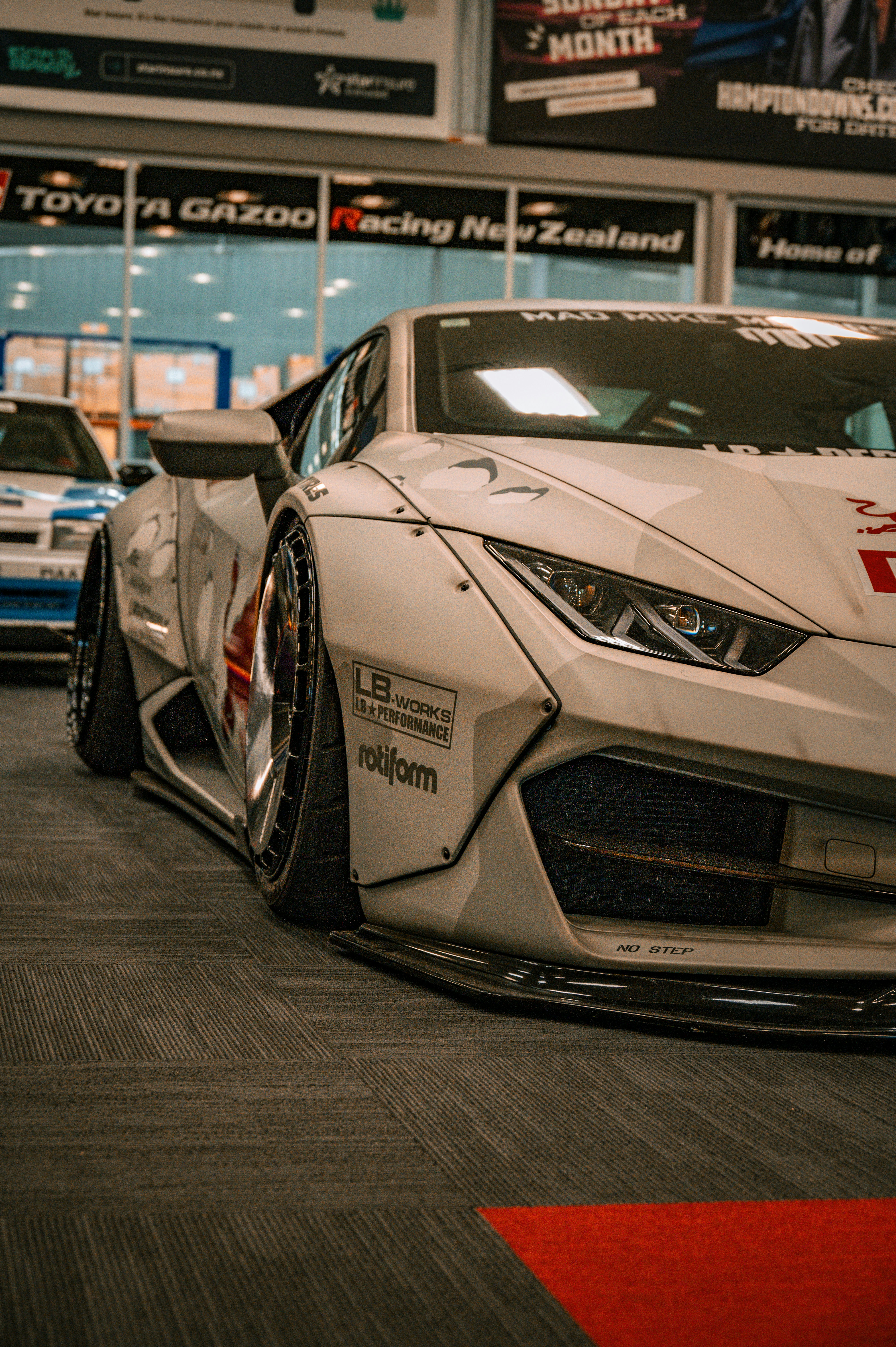Provocative white show car: widebody, carbon splitter, razor-sharp lines under showroom lighting