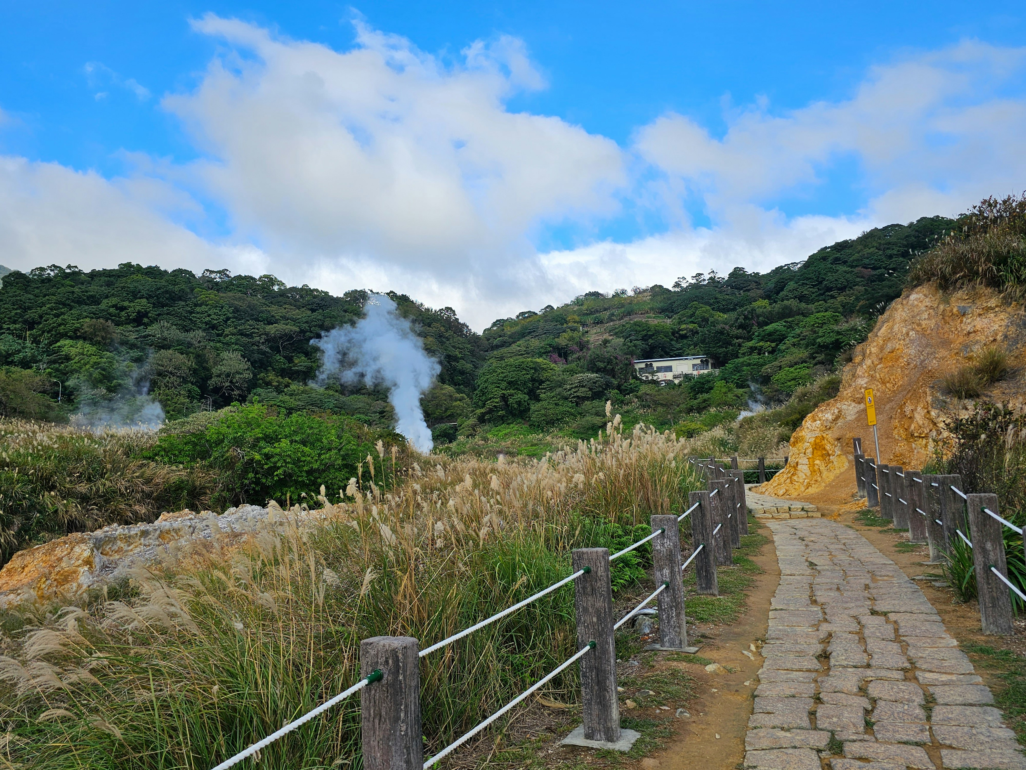 Winding Boardwalk Through Coastal Hills as Steam Rises