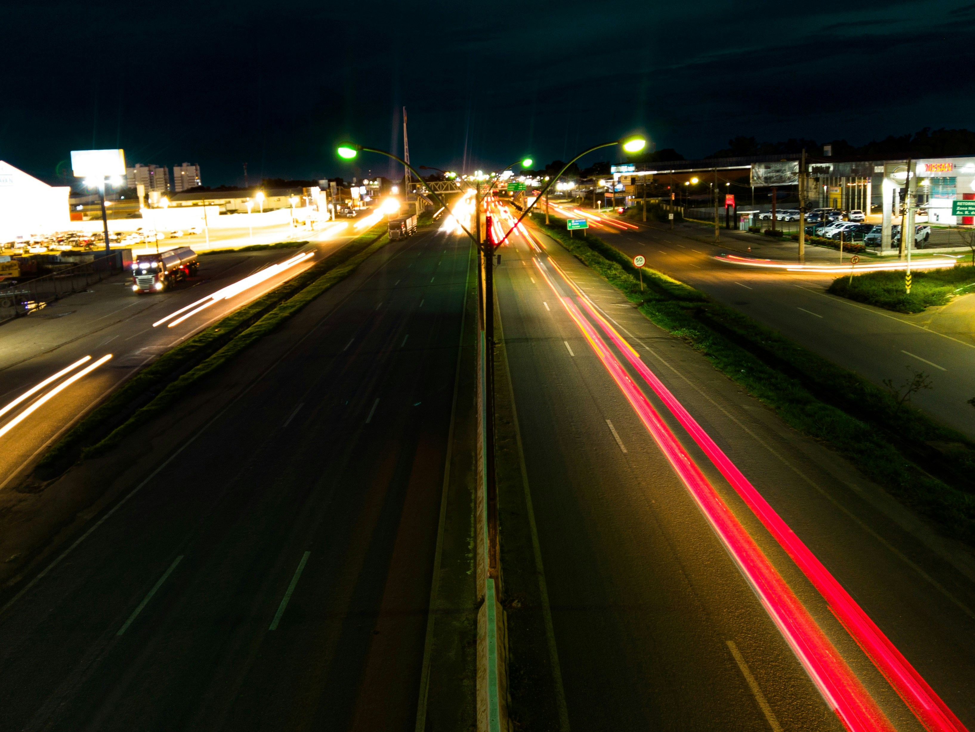 Long exposure of a busy city street at night with light trails from passing vehicles.