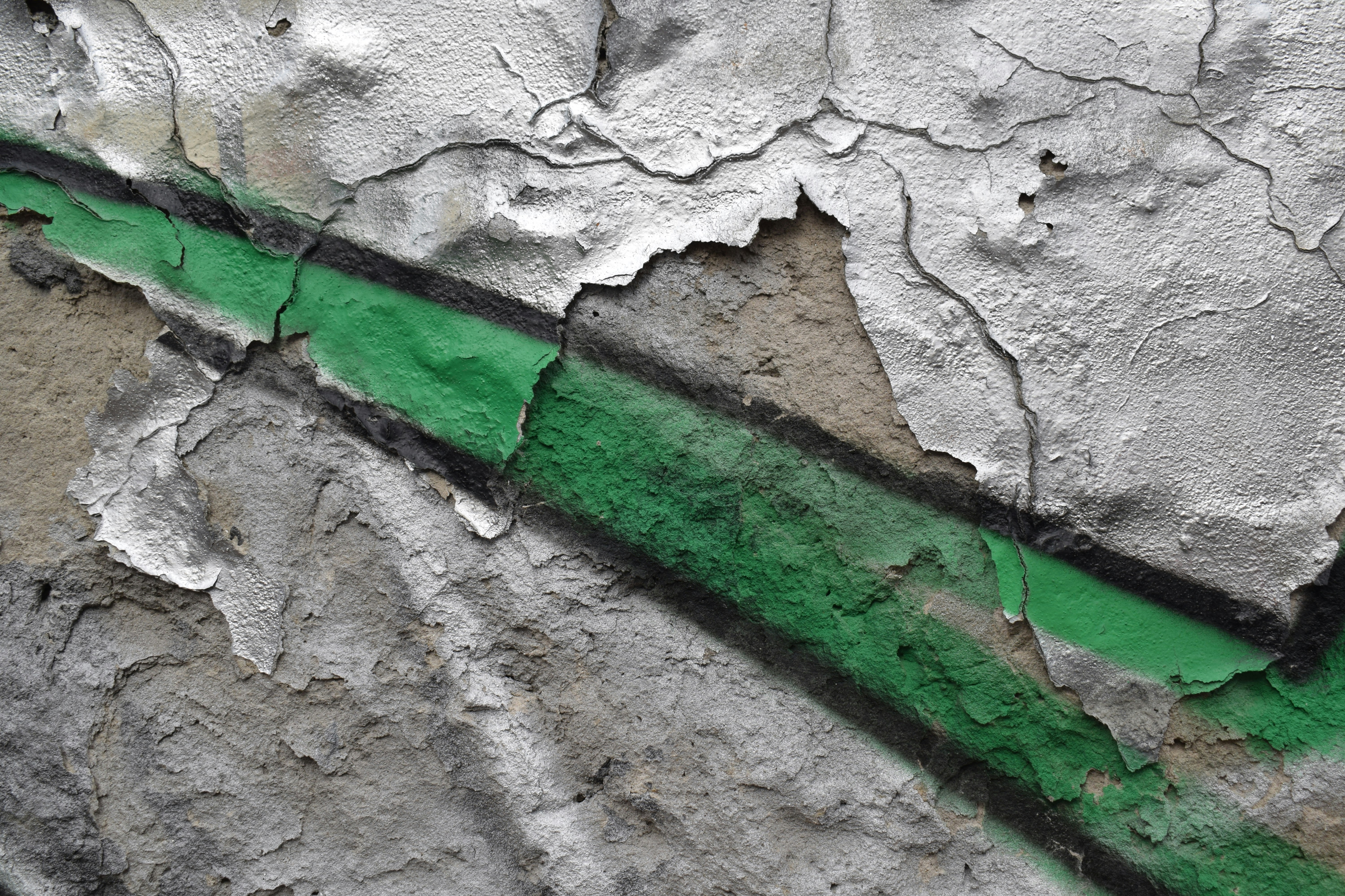 Green Diagonal Stripe across a Crumbling Concrete Facade
