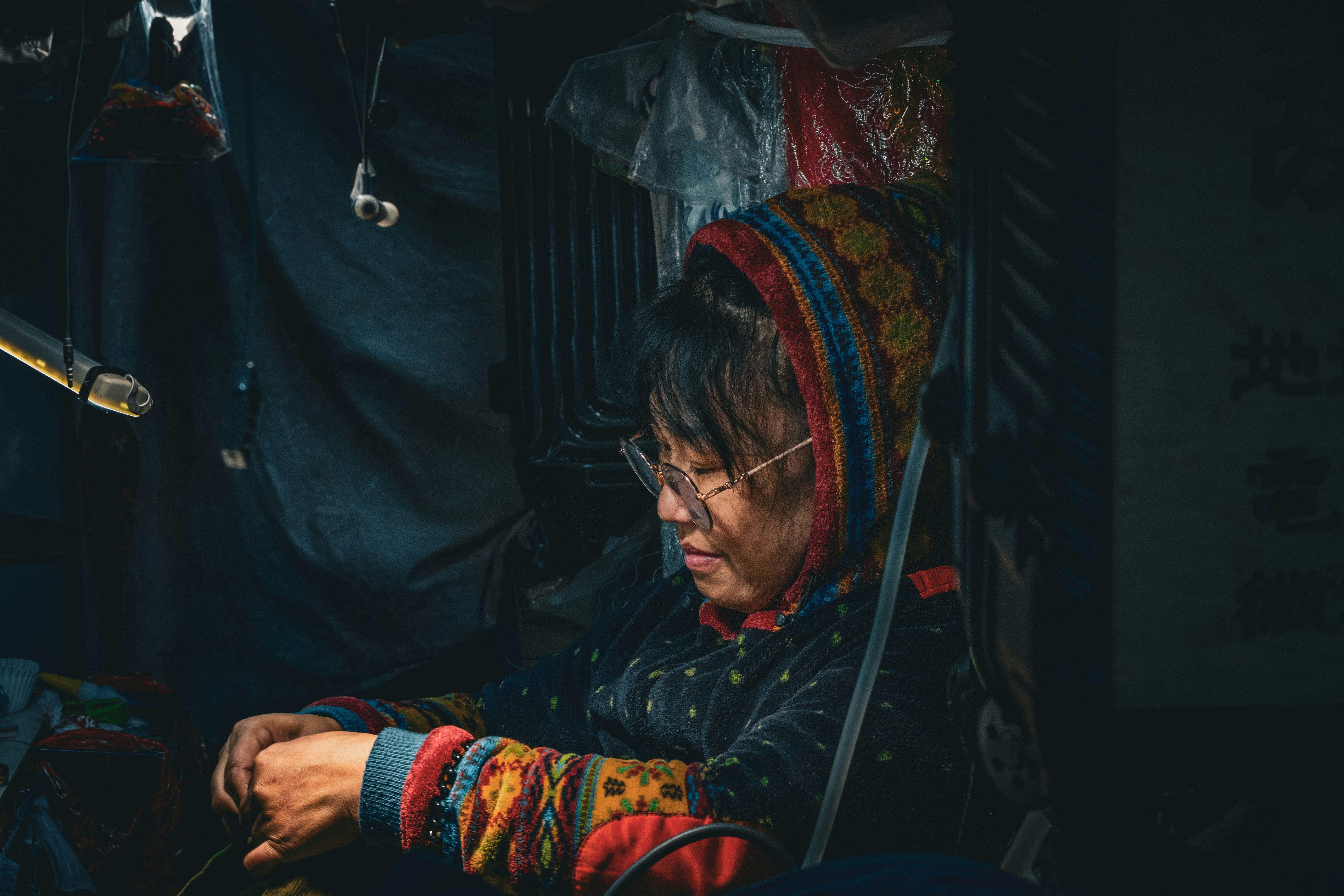 Threaded Focus: Portrait in a Dim Market Stall