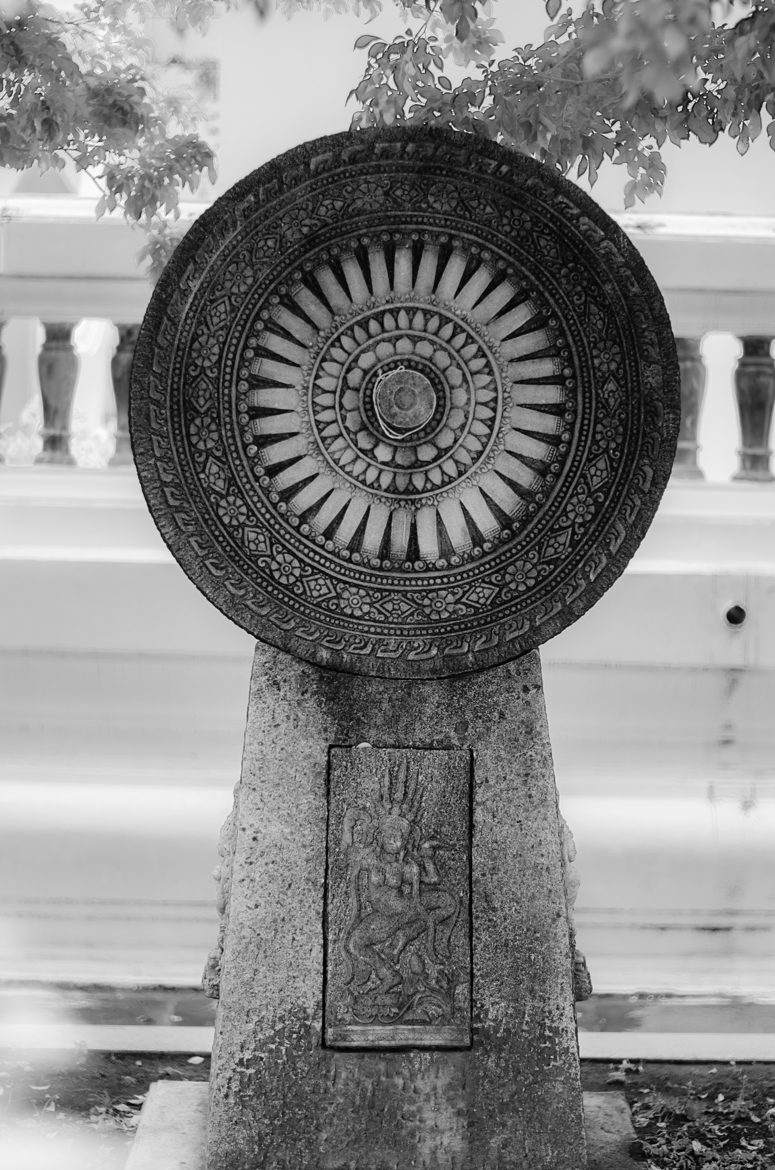 Radial Stone Wheel: A Monochrome Sentinel on a Carved Pedestal