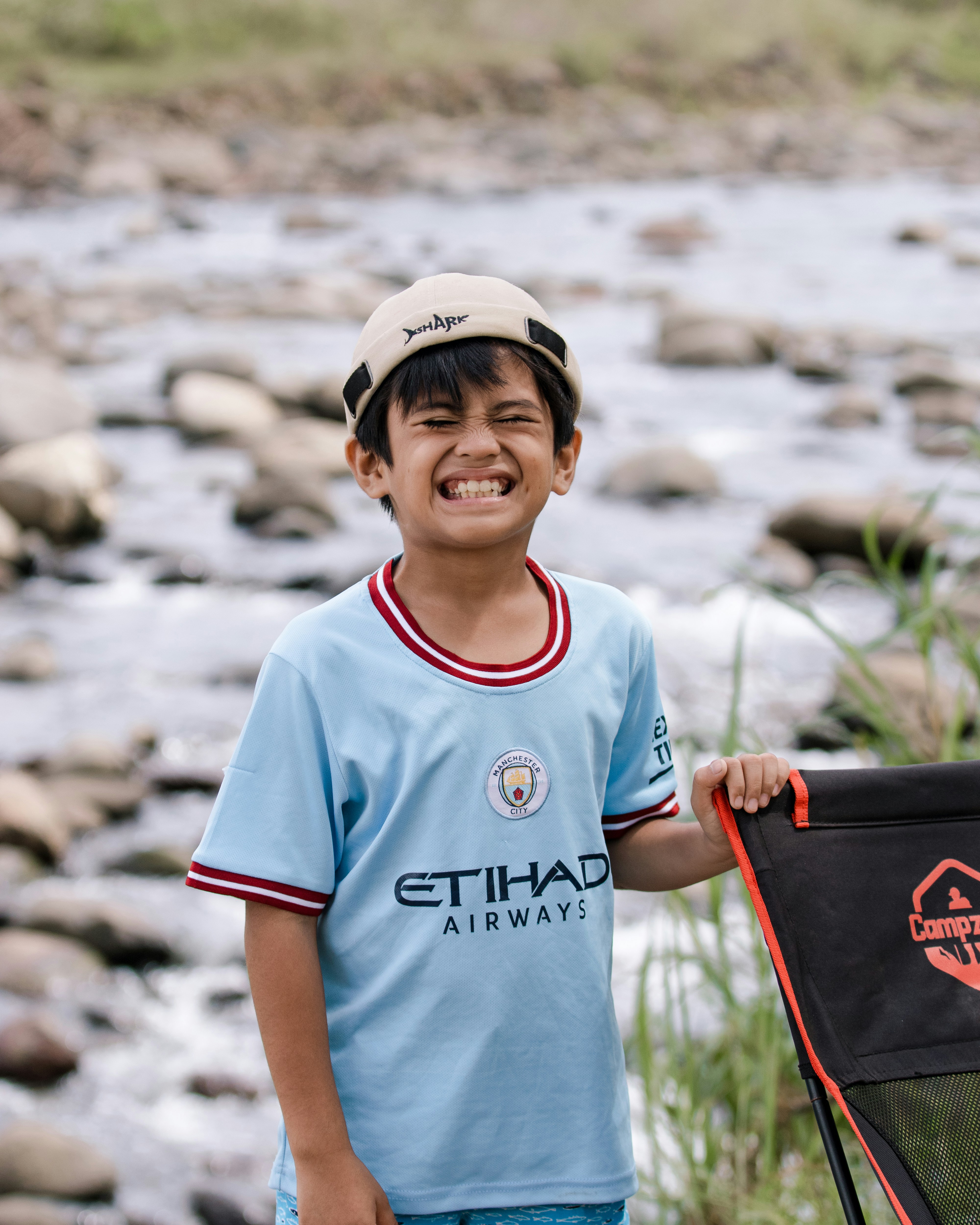 a young boy holding a kite next to a river