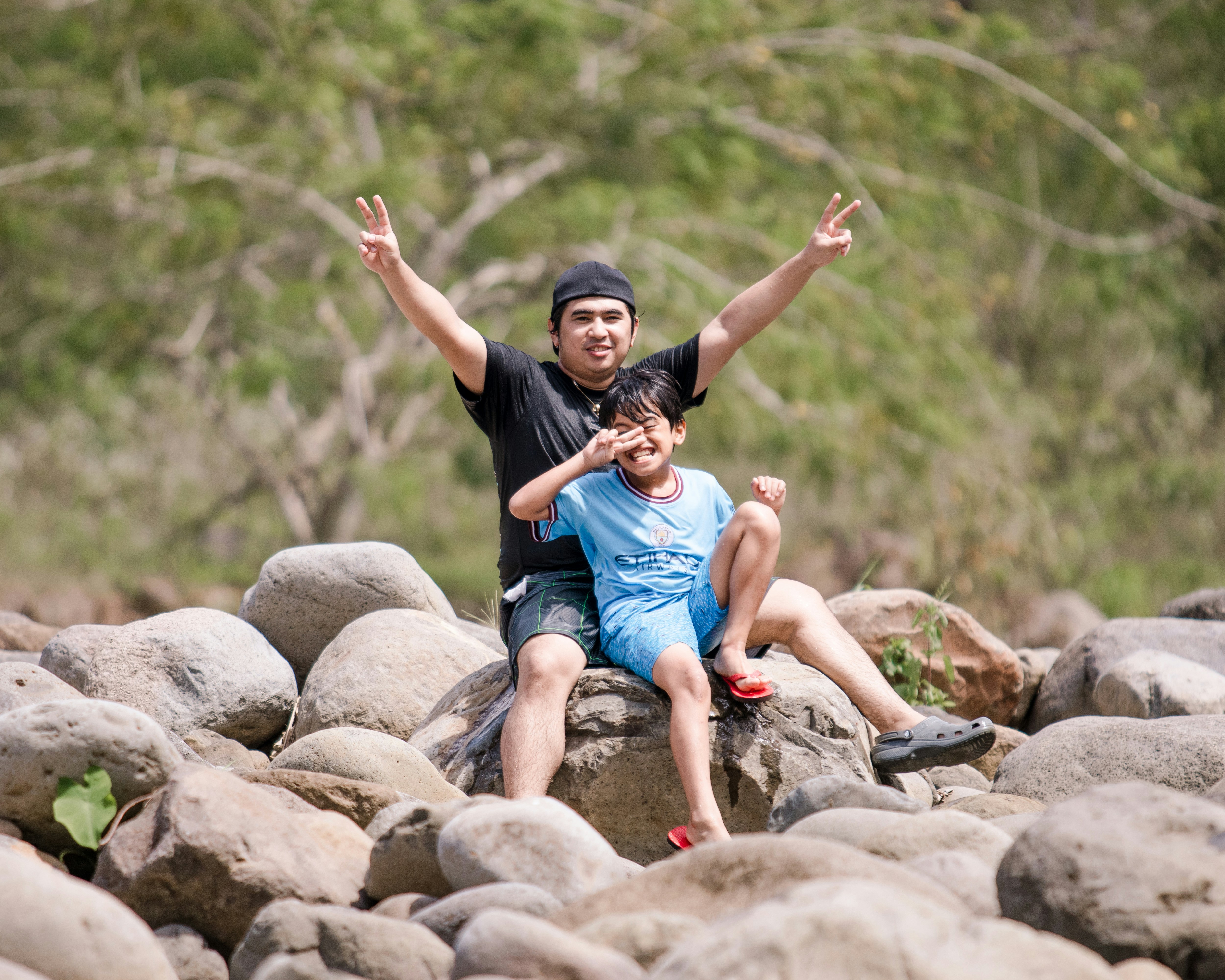 Riverside siblings: victory pose on smooth stones