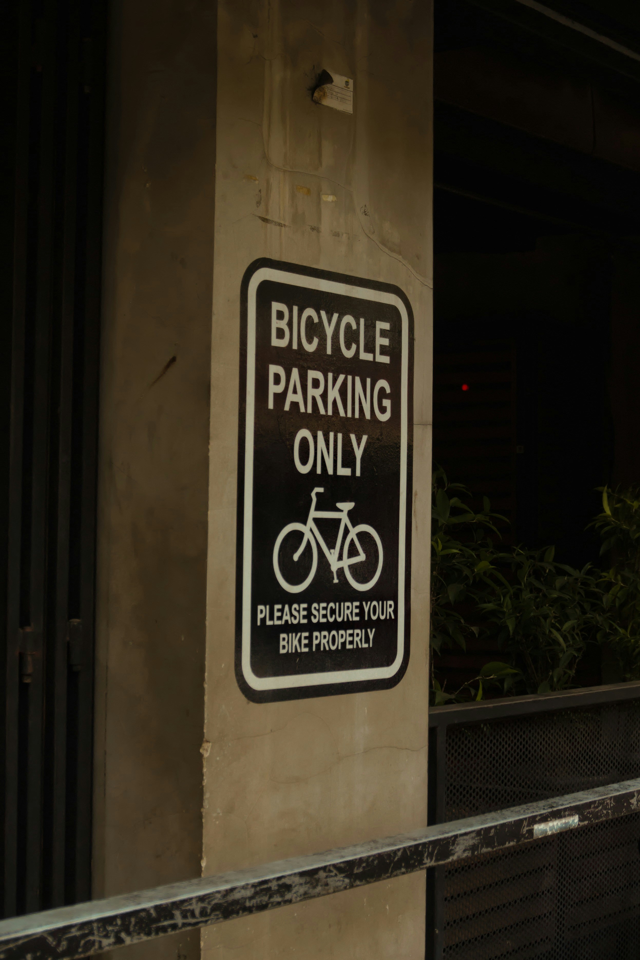 Concrete Pillar Sign: Bicycle Parking Only in a Dim Indoor Lot