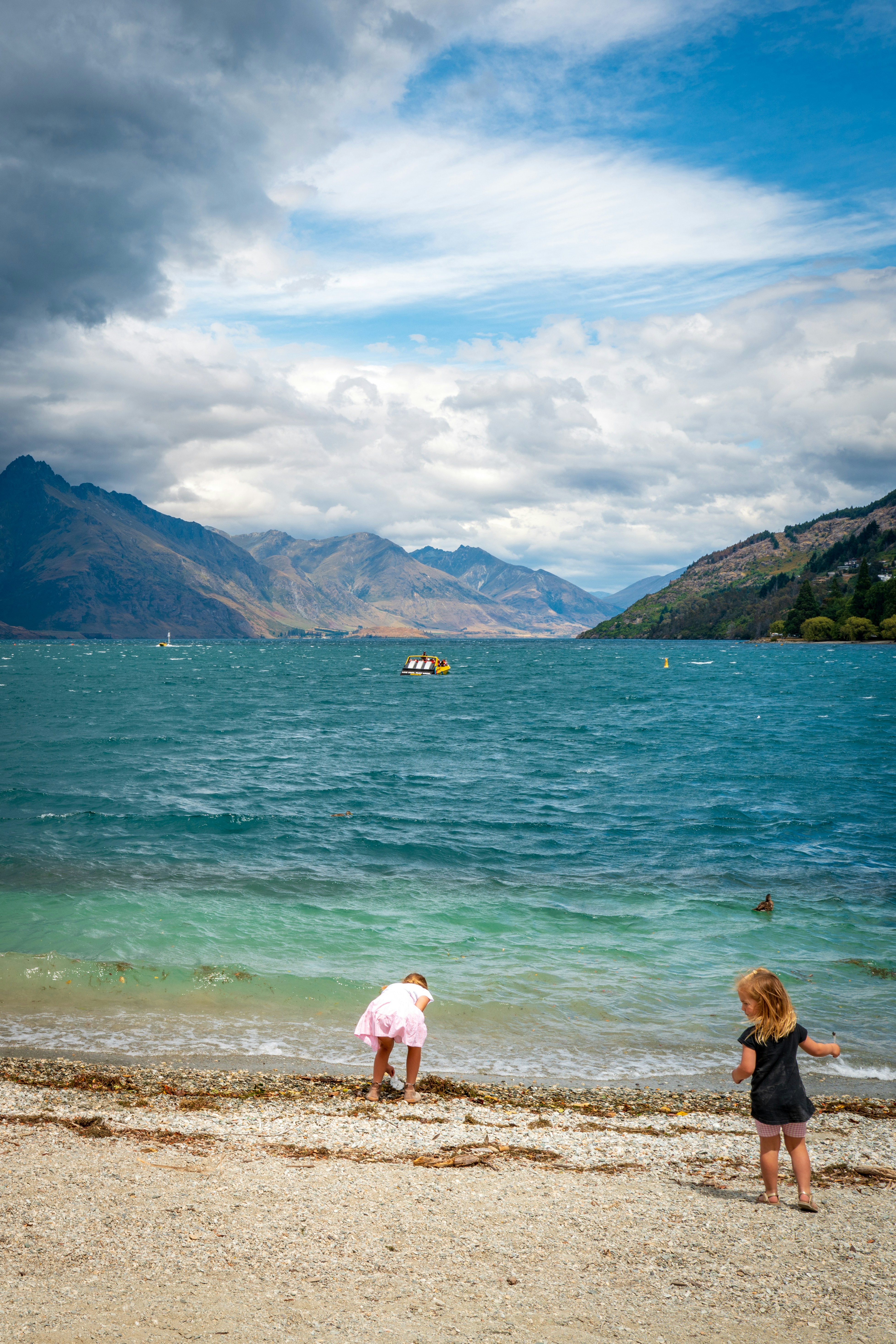 Pebble Beach Moment: Two Children at the Turquoise Alpine Lake Edge